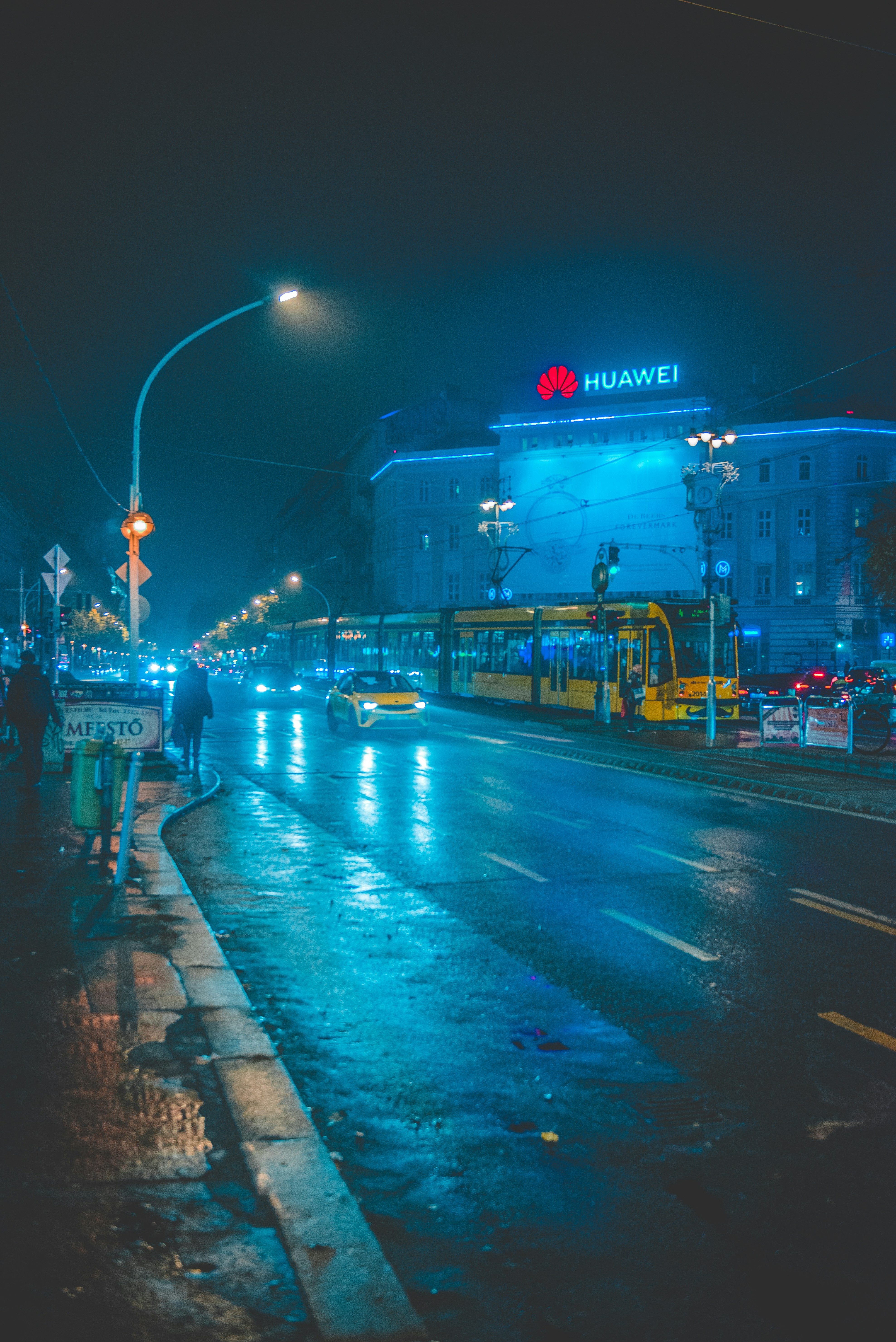 Blue Neon Crossroads: Huawei Sign Illuminates a Rain-Slick City Street