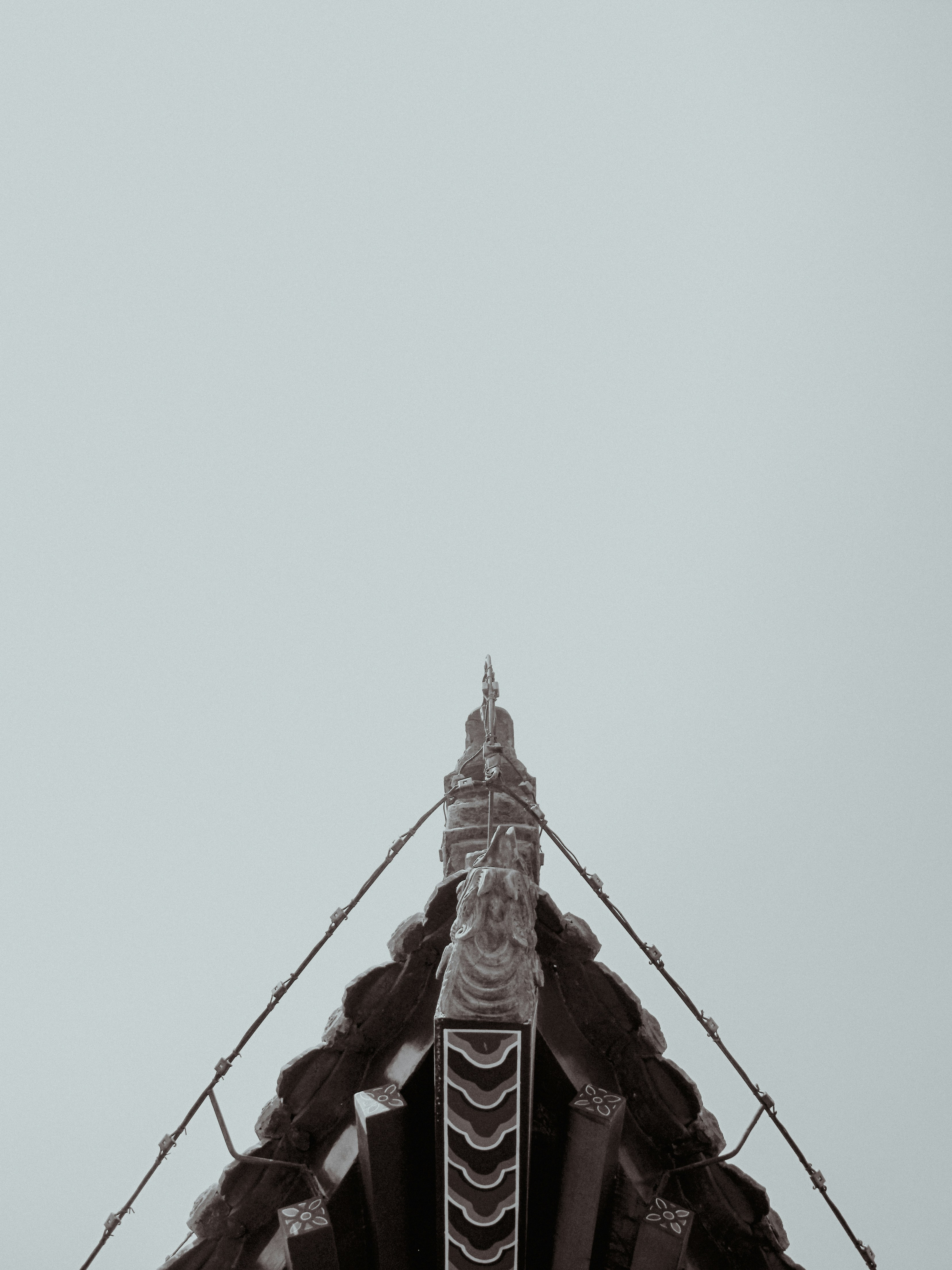 Intricate architectural details of a temple's spire captured in black and white, emphasizing its craftsmanship and design. The image highlights the symmetry and artistry of the structure.