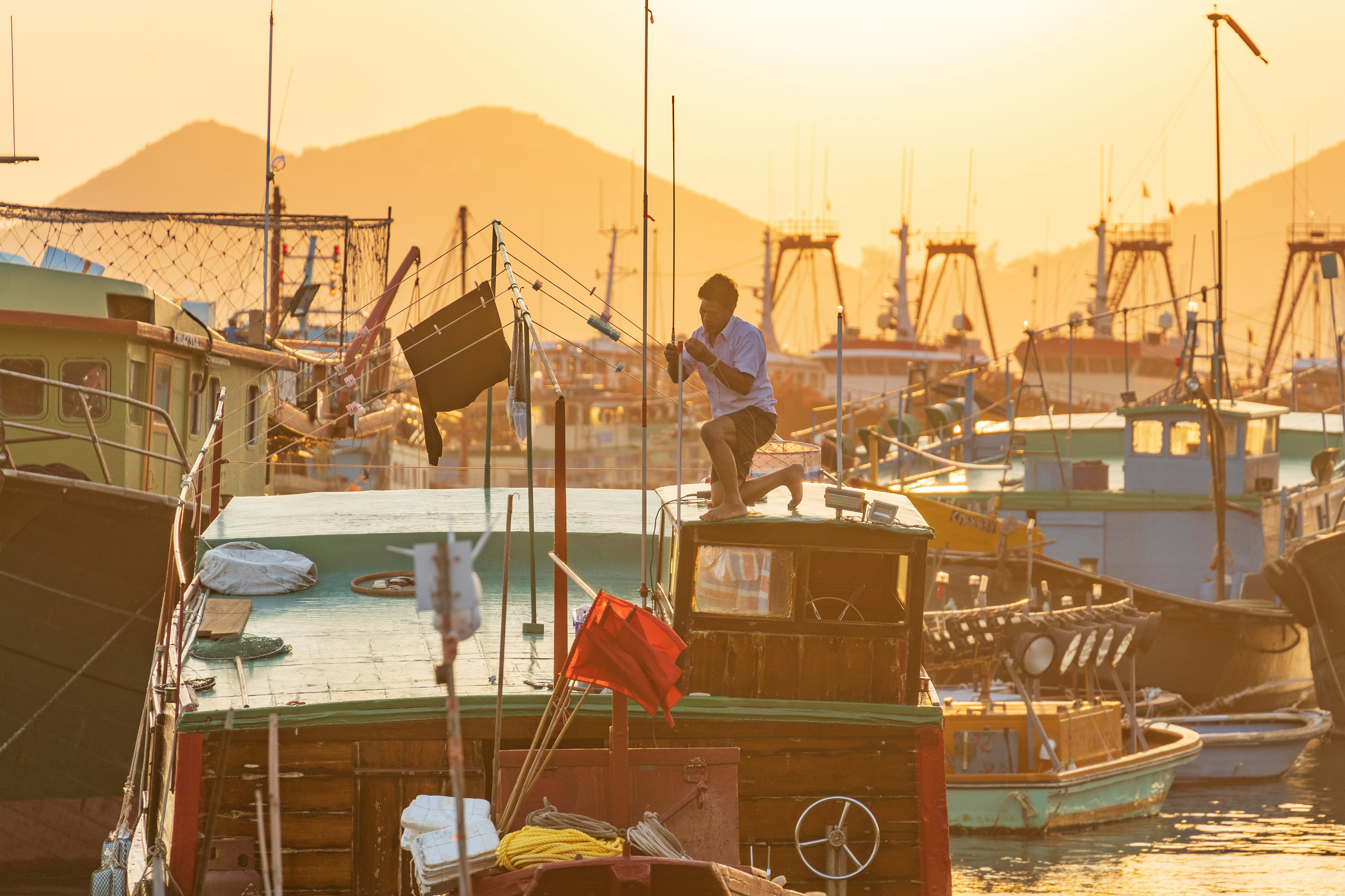 A man standing on top of a boat in a harbor photo – Free Hong kong ...