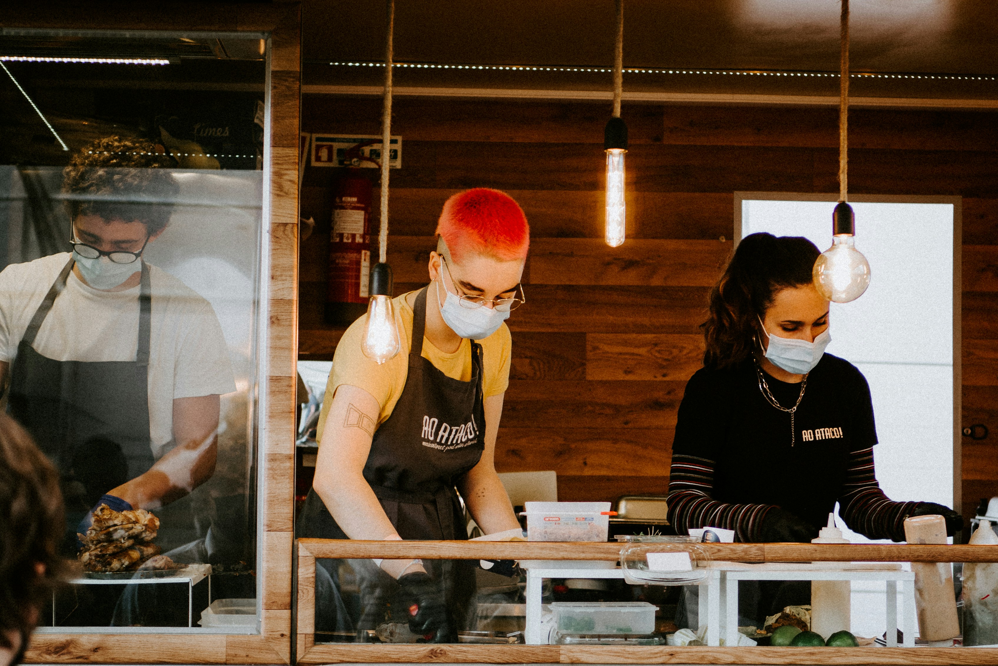 Three culinary artists engaged in food preparation within a vibrant food stall, showcasing teamwork and creativity.