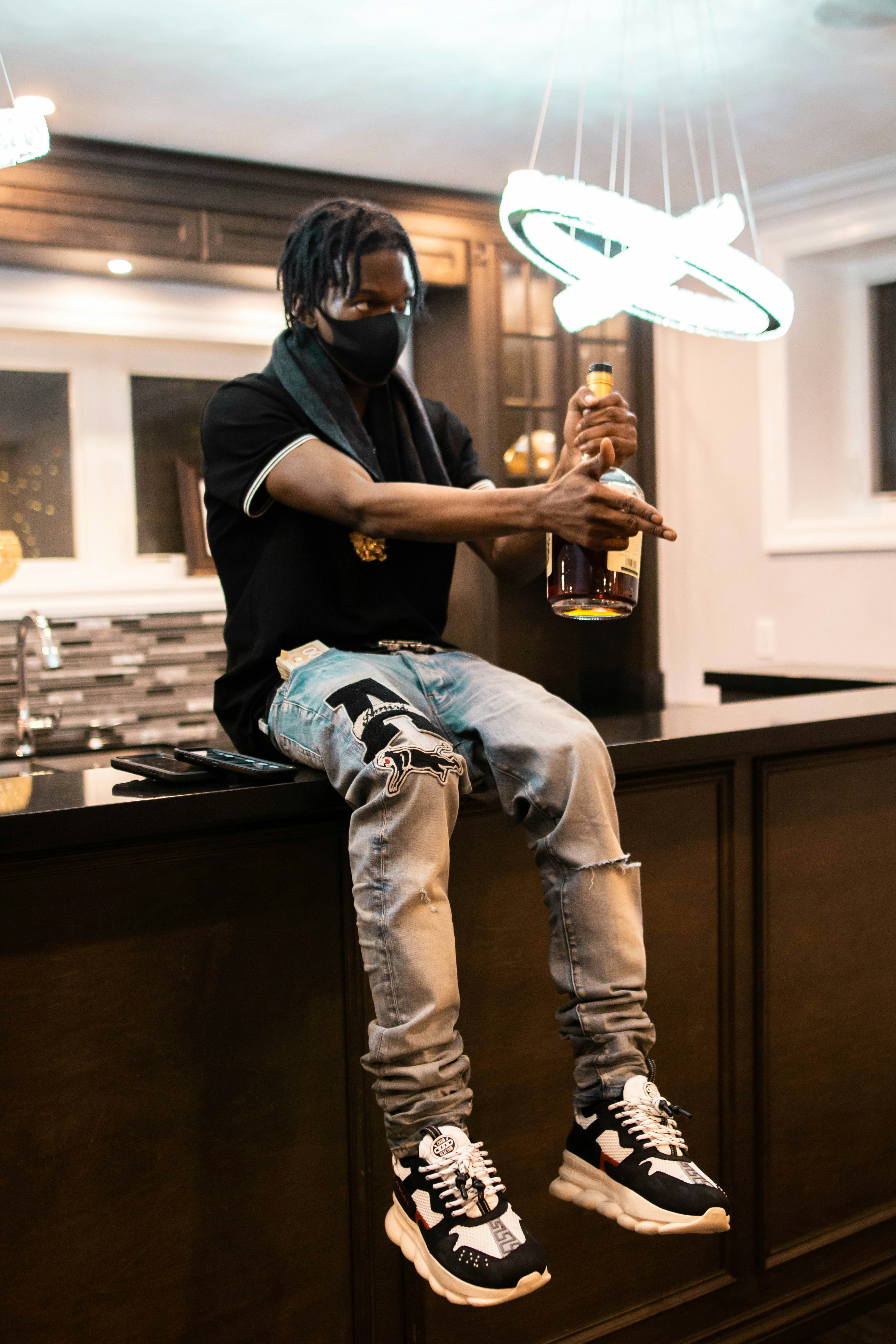 Un hombre sentado encima de un mostrador sosteniendo una botella foto ...