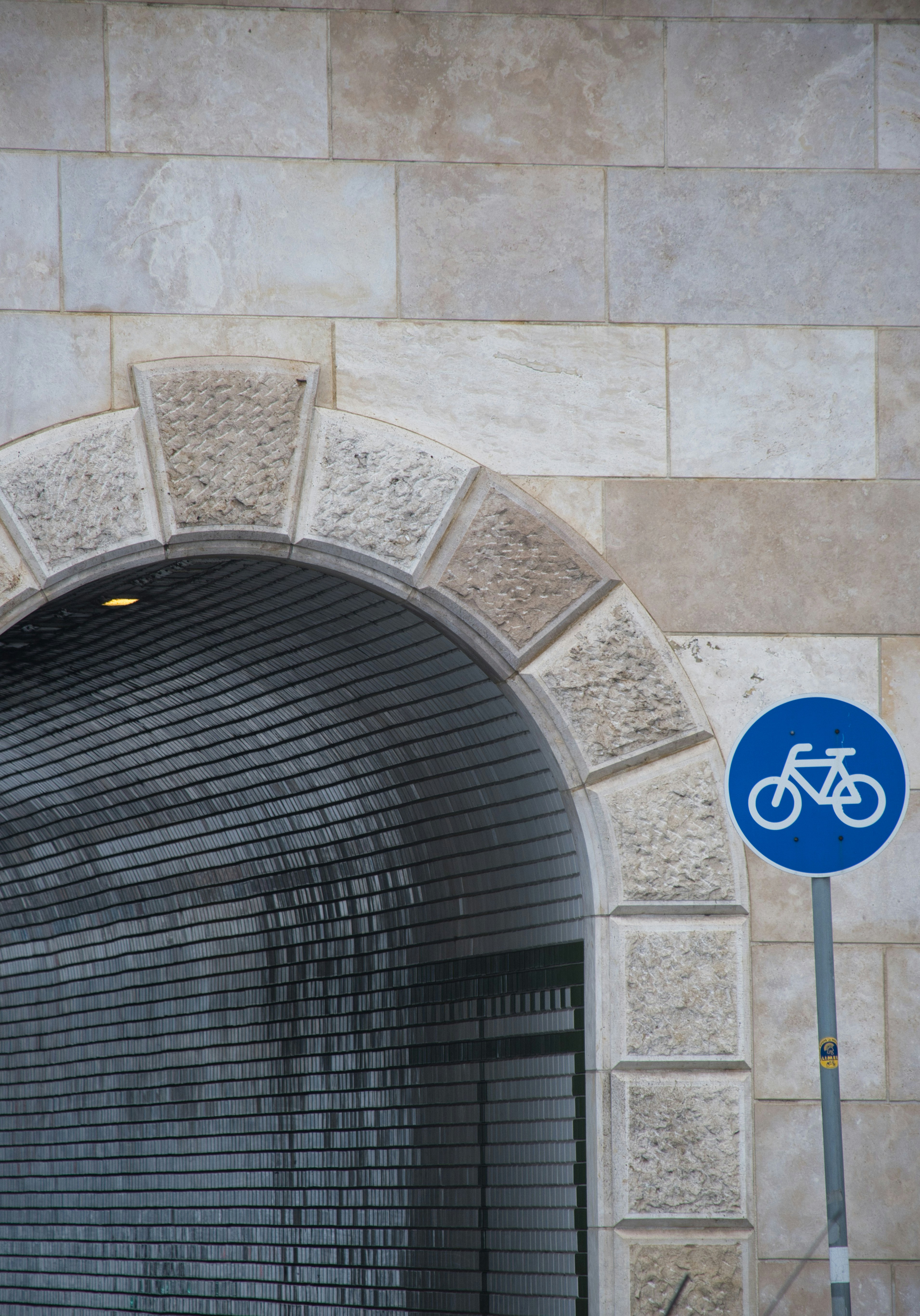 Blue Bicycle Sign Framing a Stone Archway