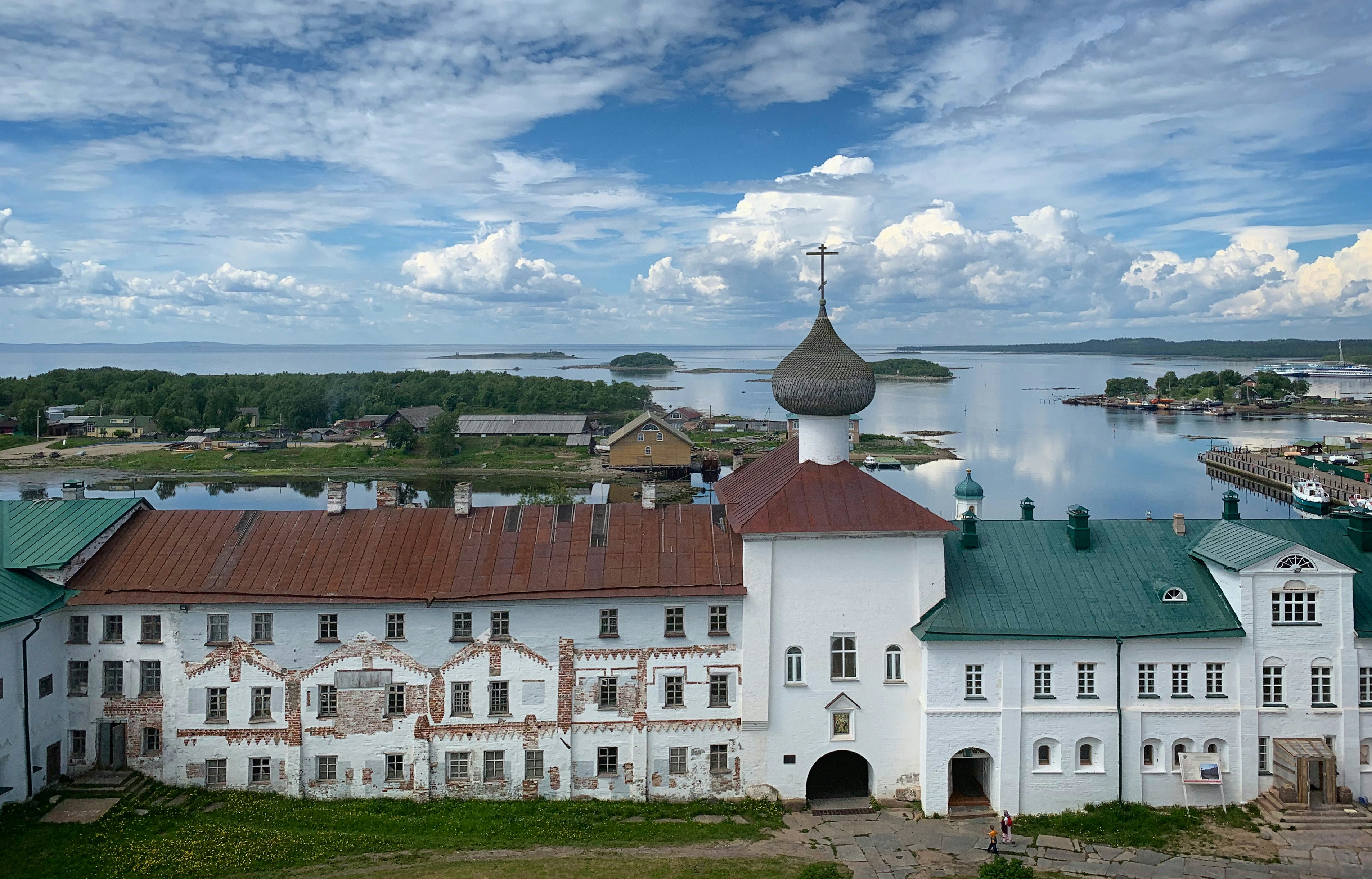 Historic monastery complex with distinctive architecture reflecting cultural heritage, set against a serene waterfront and cloudy sky.