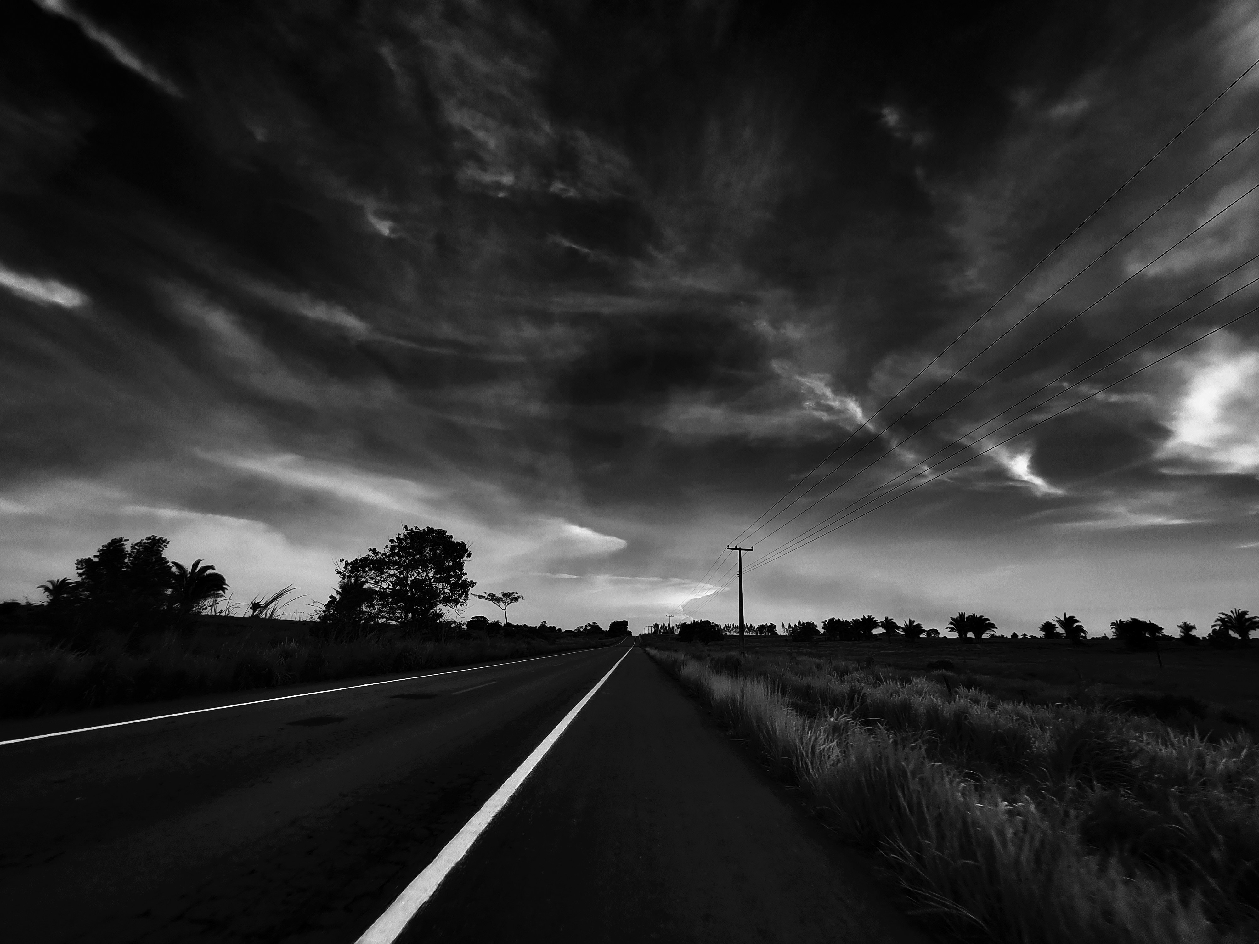 A desolate road stretches into the horizon under a dramatic sky, evoking a sense of solitude and adventure.