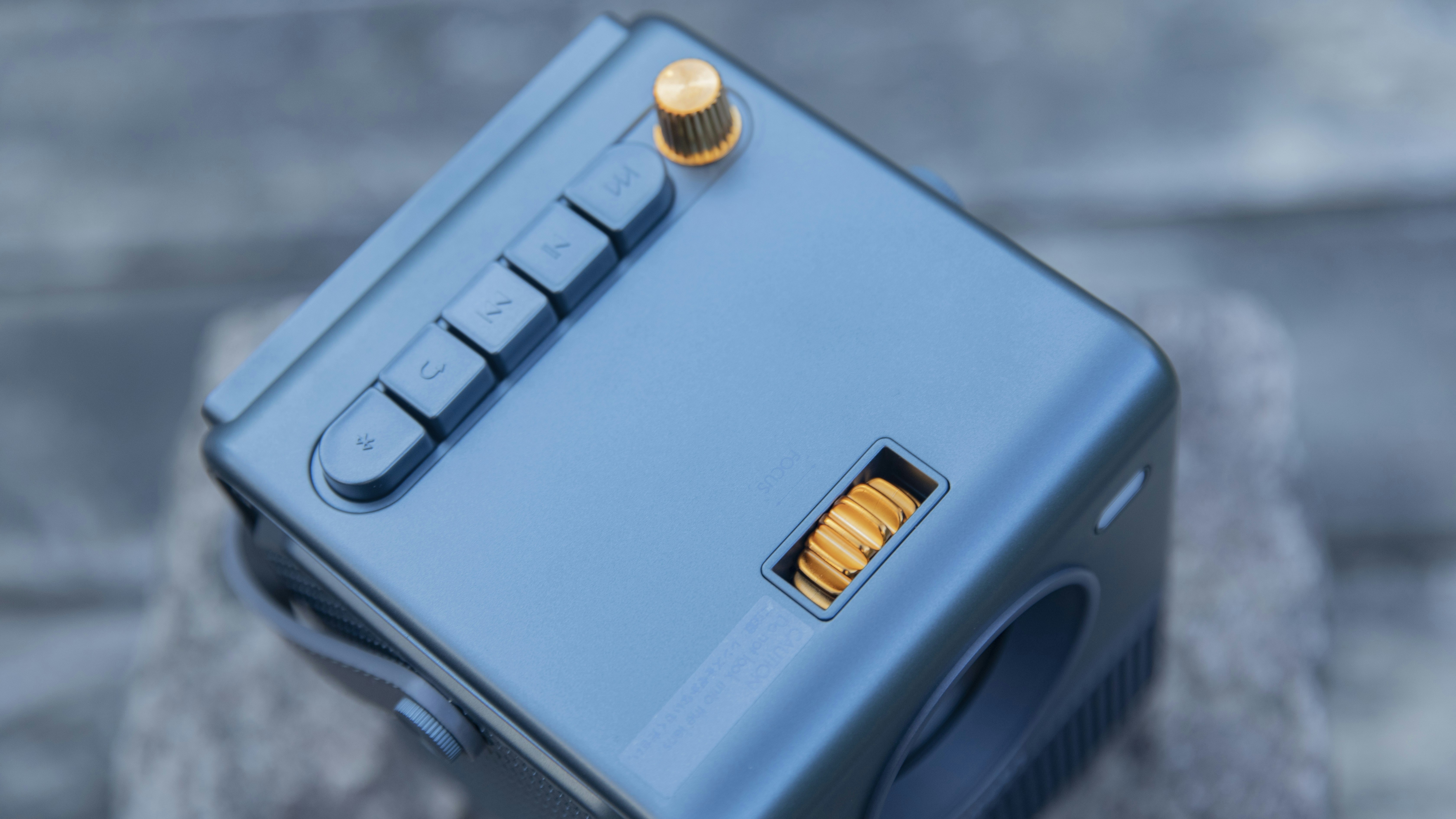 A small blue device with a gold button on it photo – Free Lcd projector ...