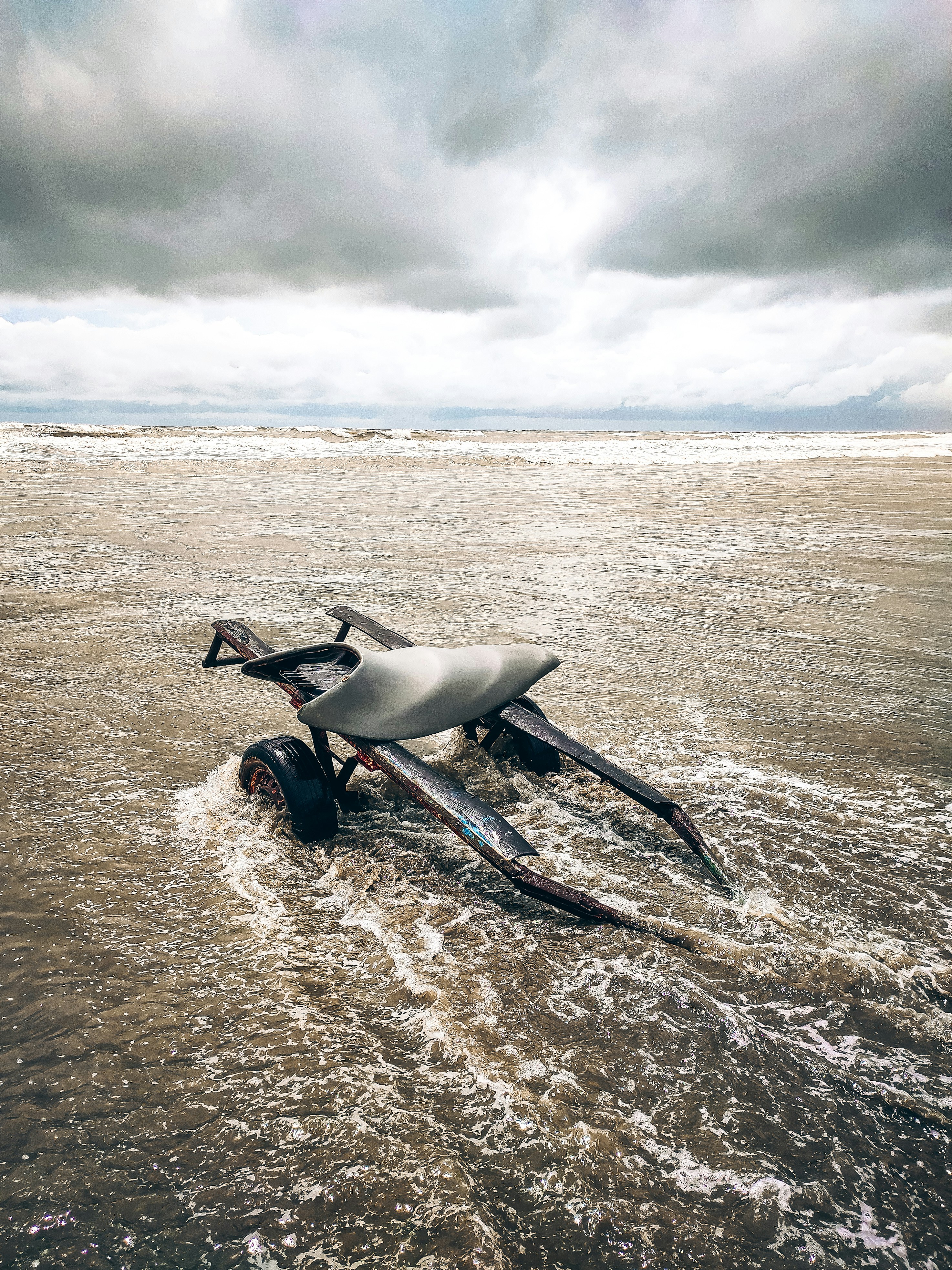 Drifted Wreck at the Edge of Tide: A Rusted Cart Adrift on a Cloudy Shore