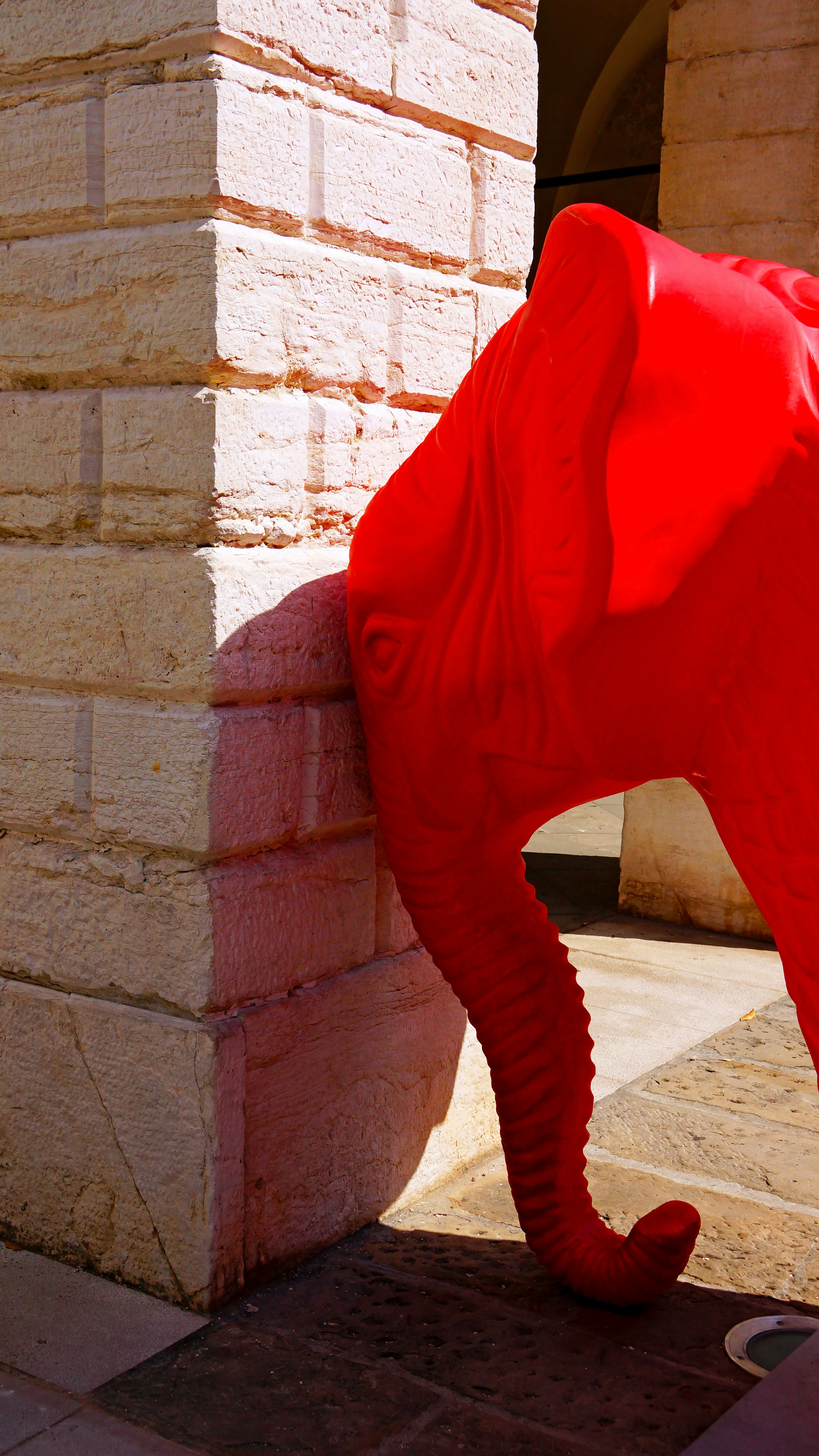 A red elephant statue leaning against a brick wall photo – Free Human ...
