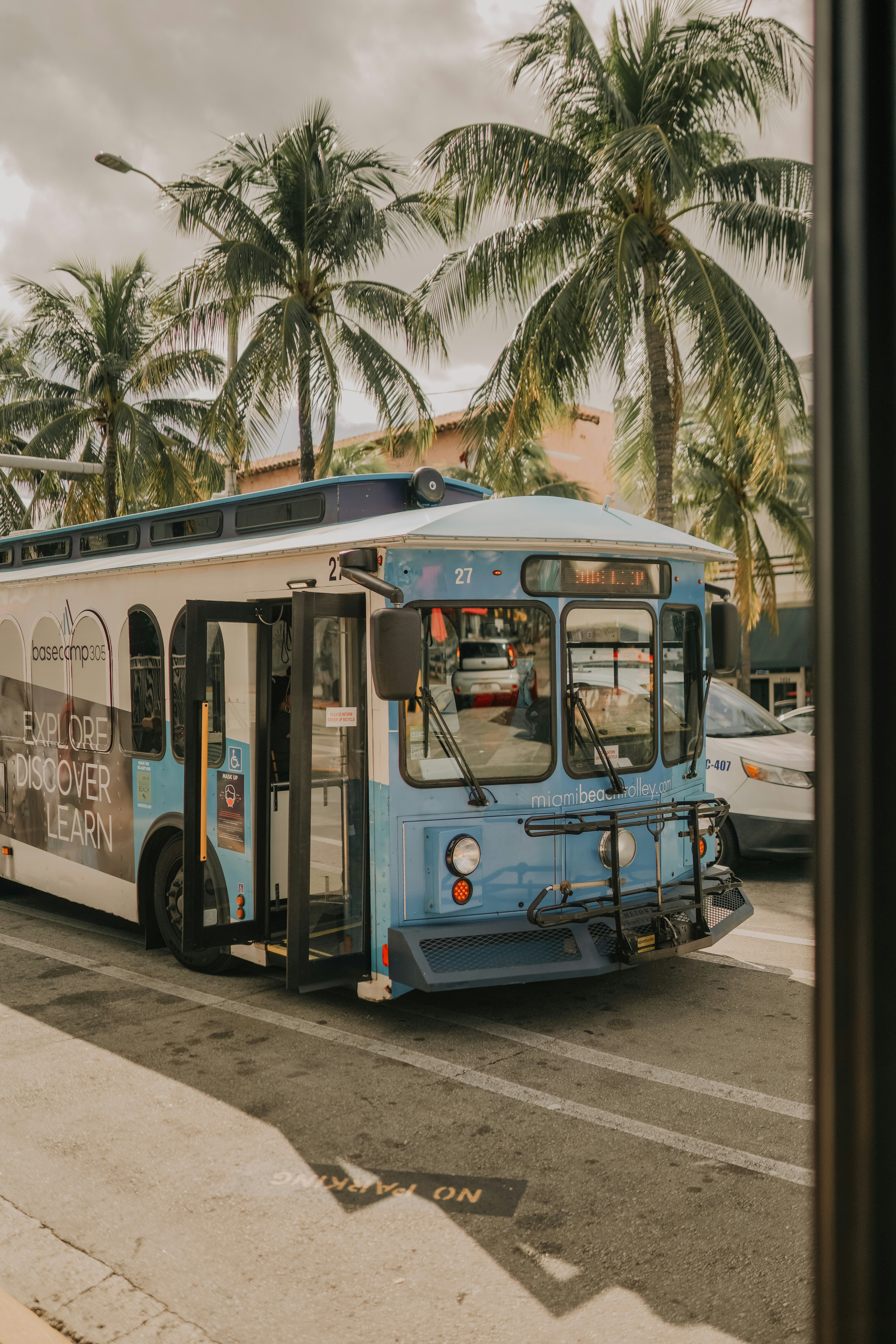 Un bus bleu et blanc descendant une rue à côté de palmiers photo ...