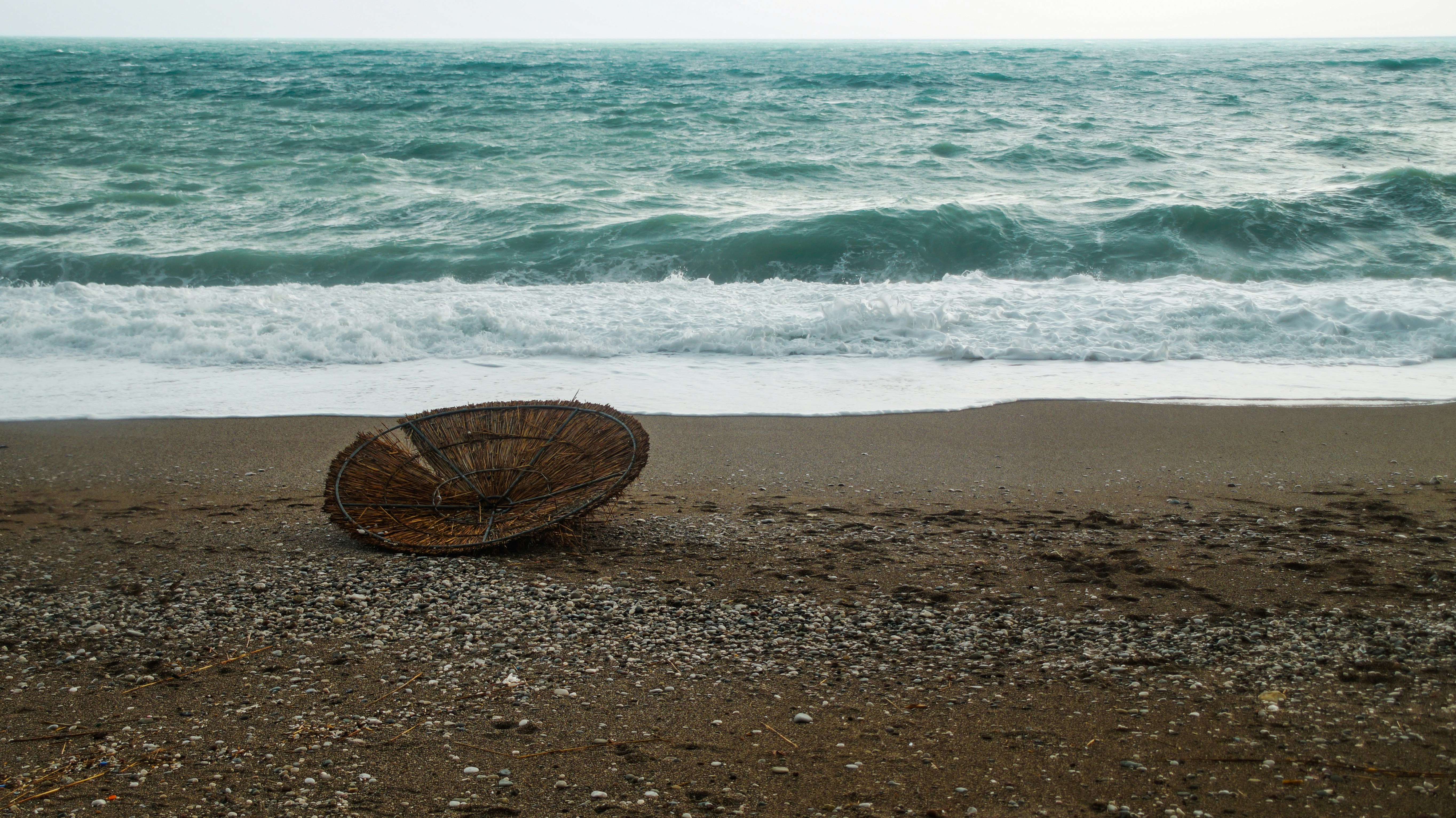 a basket sitting on top of a sandy beach next to the ocean