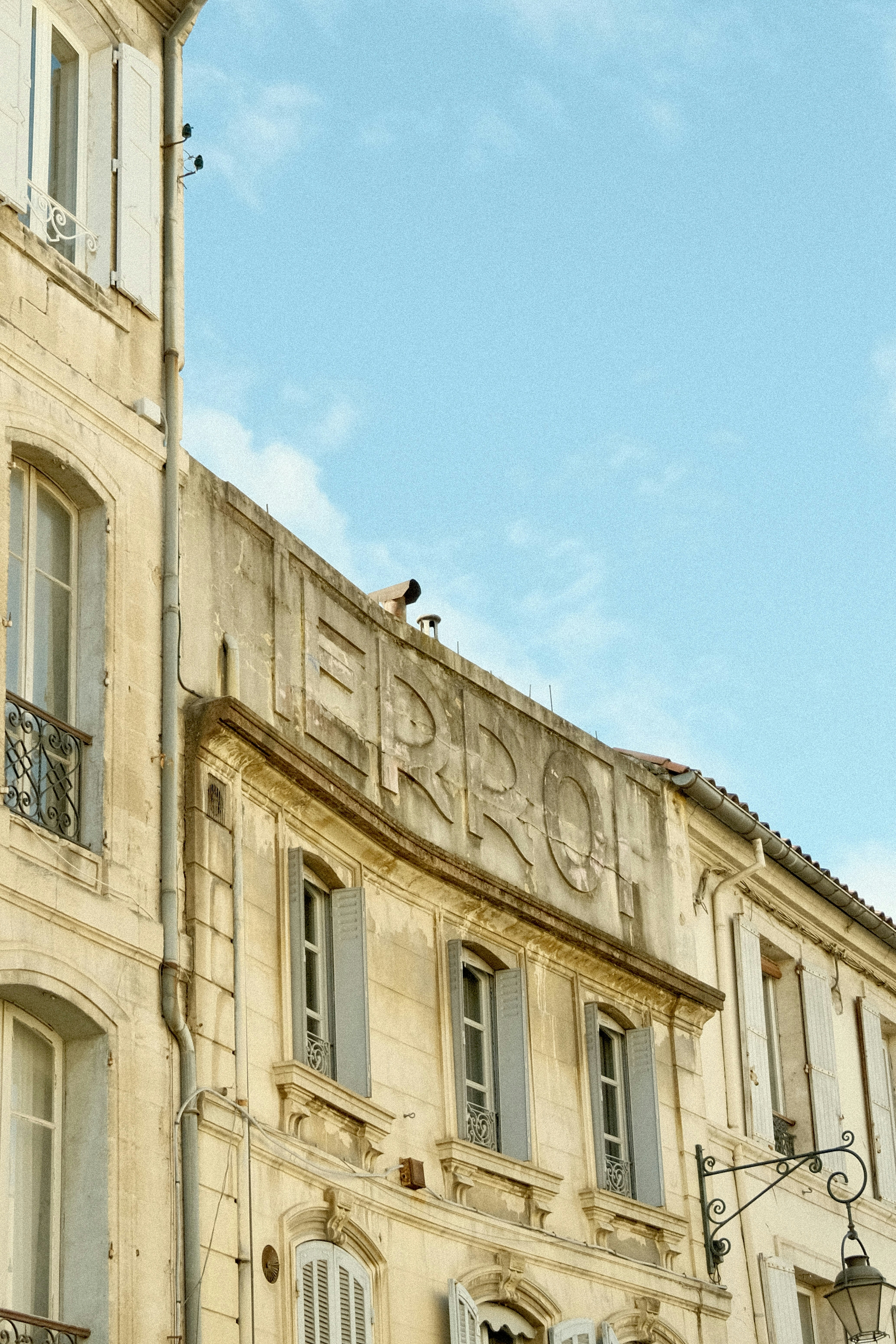 Weathered Grandeur: Sunlit Crest of a Historic Facade