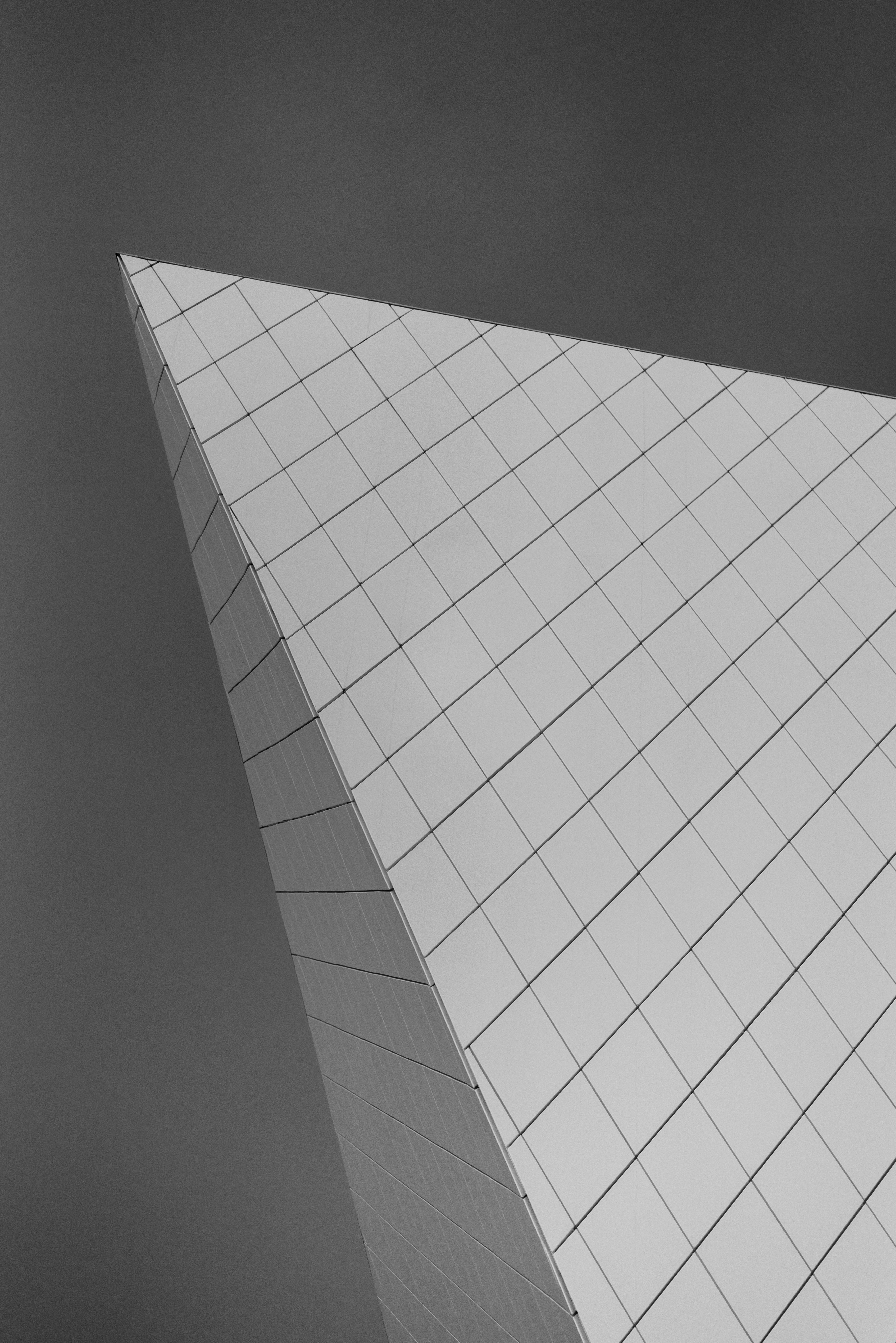 Sharp-edged architectural structure reflecting light and shadows against a dramatic sky.