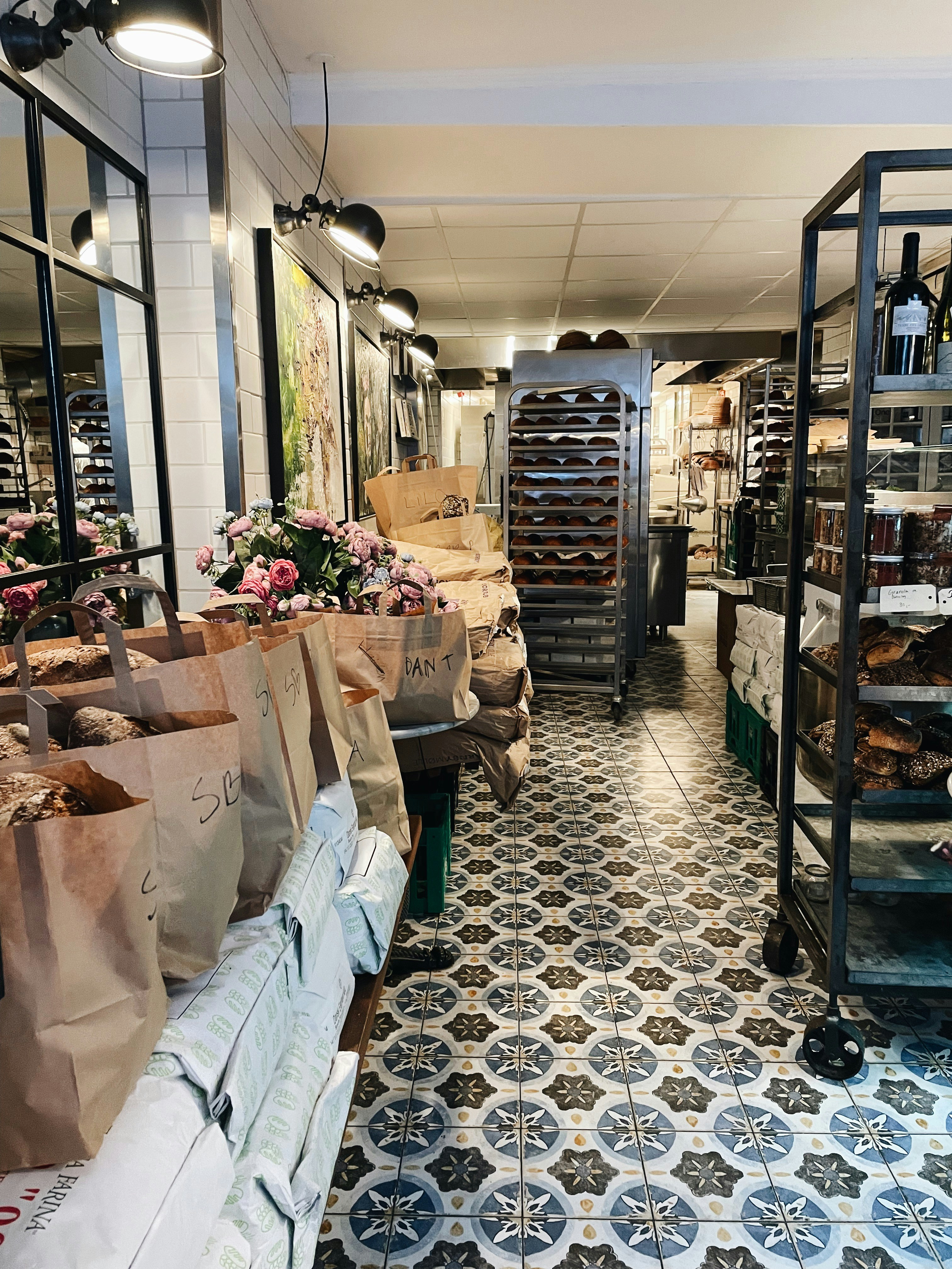 A cozy bakery shop corridor lined with paper bags and floral arrangements