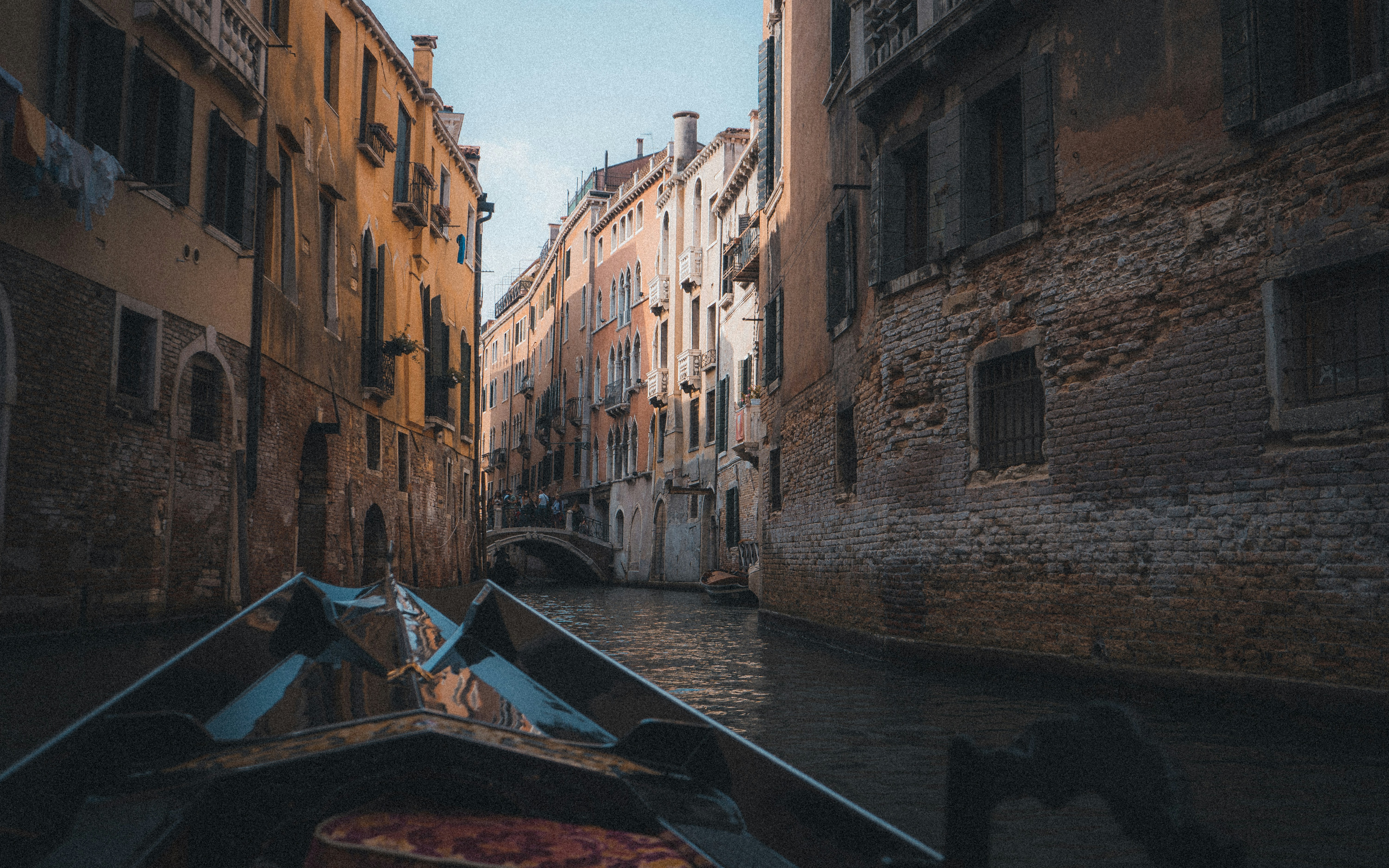 Gondola gliding through narrow Venetian canal flanked by historic buildings under a clear sky.