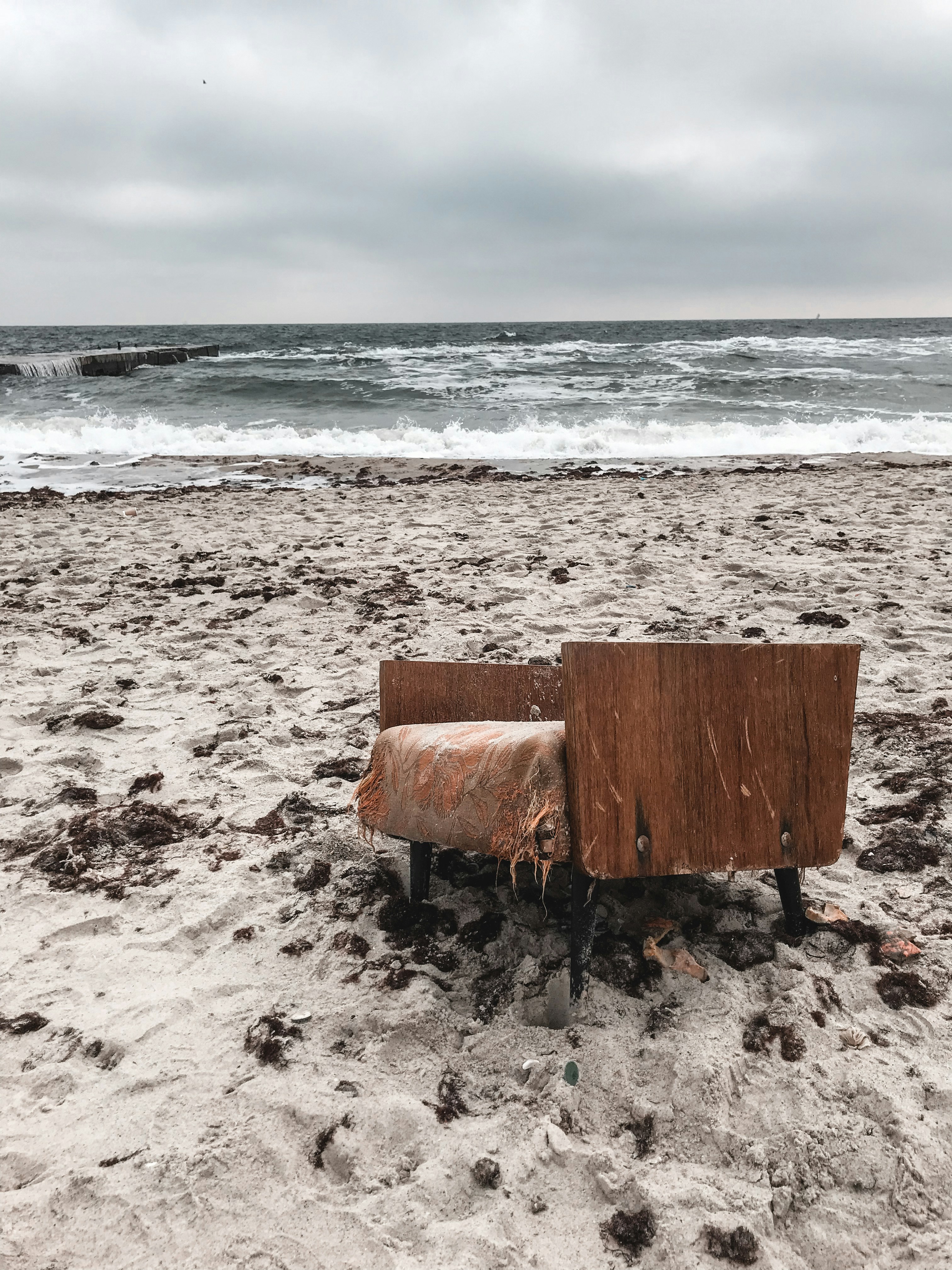 Weathered bench at the shoreline: salt-stained wood and restless surf