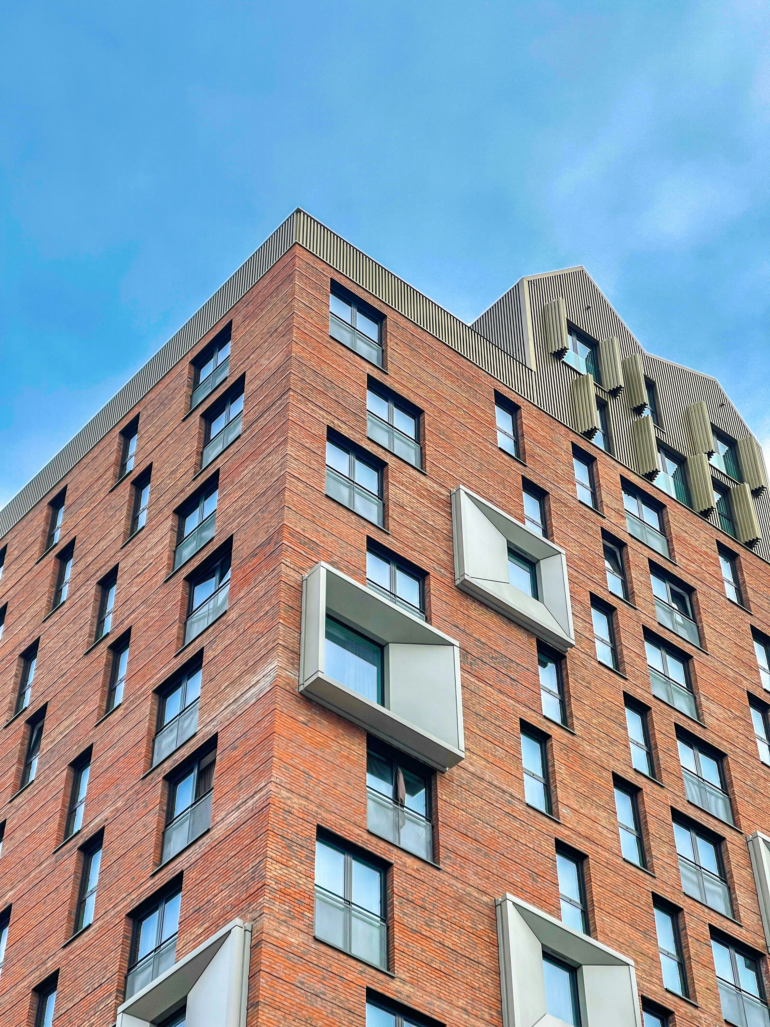 A tall brick building with windows and balconies photo – Free United ...