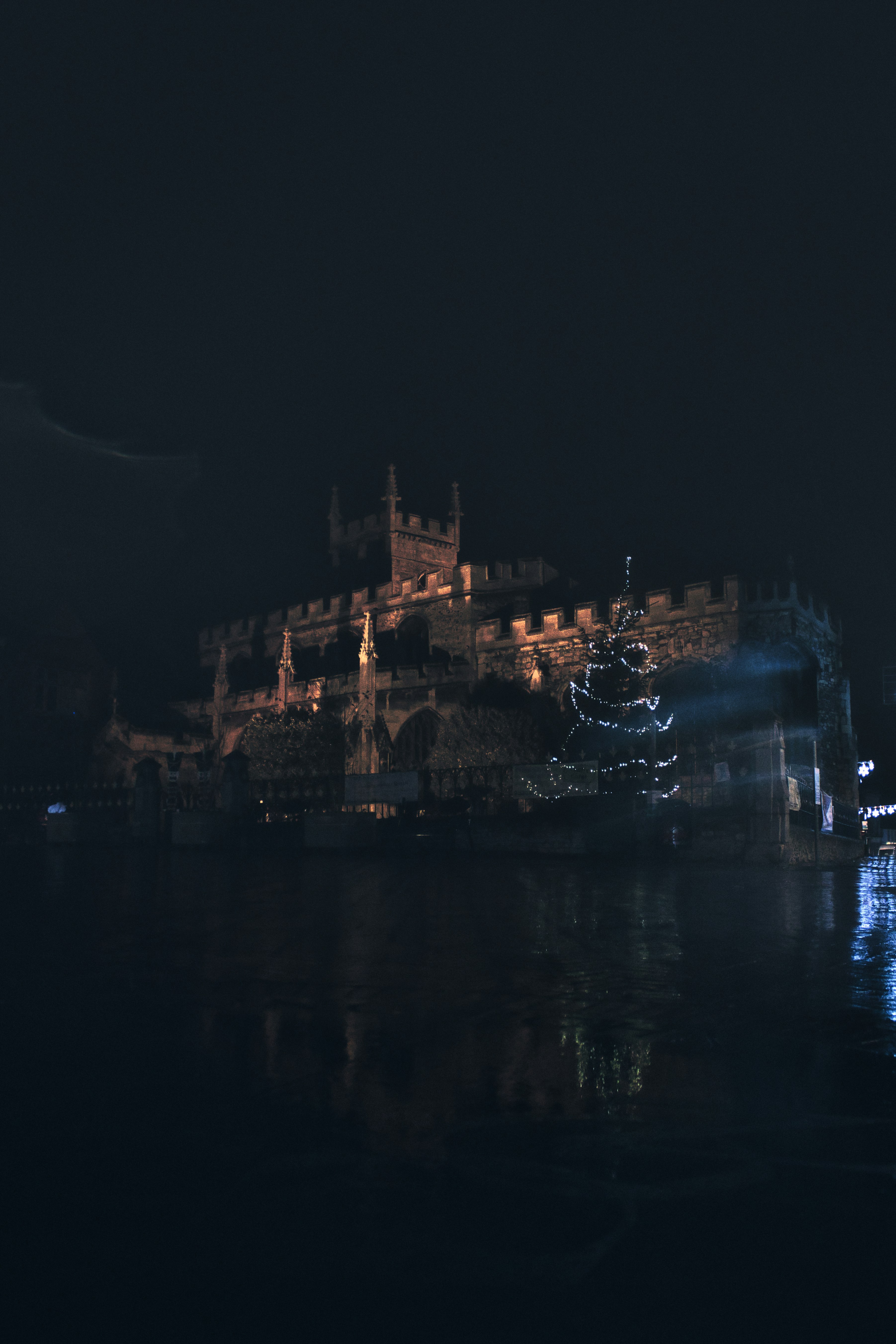 A castle lit up at night with lights reflecting in the water photo ...