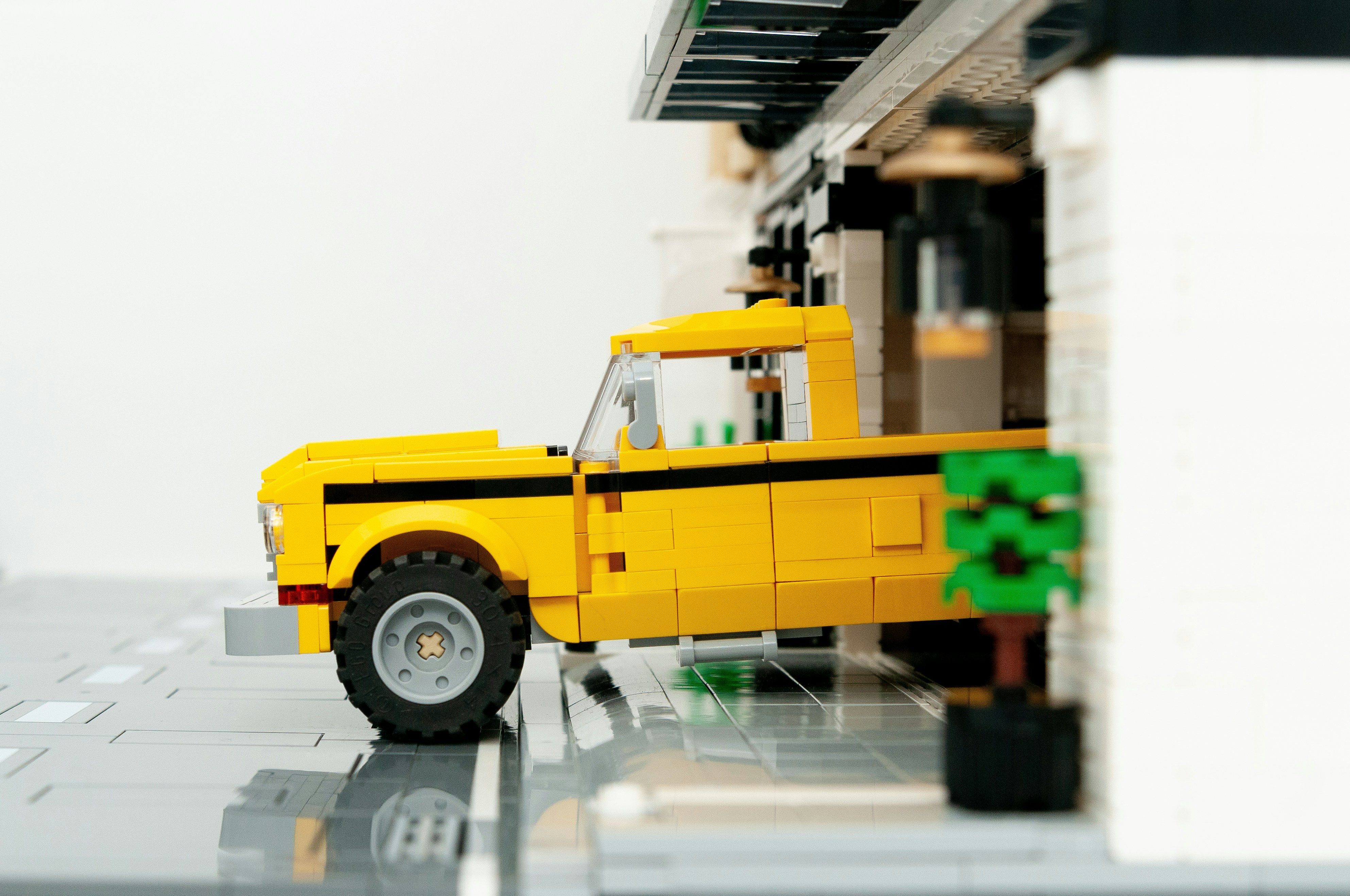 A vibrant yellow LEGO truck partially emerges from a garage, showcasing intricate details of the brick construction and the surrounding environment.