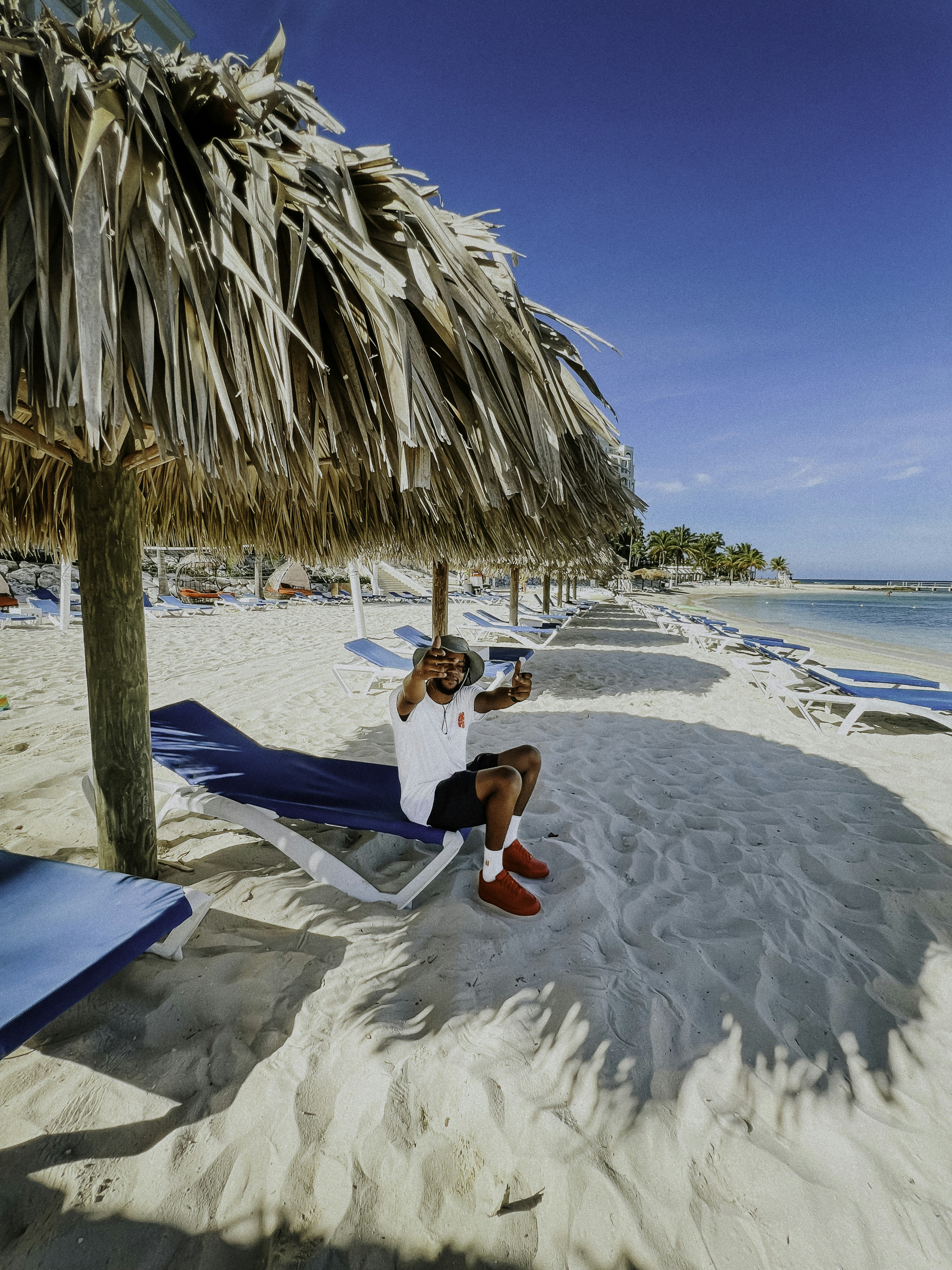 a man sitting under a straw umbrella on a beach