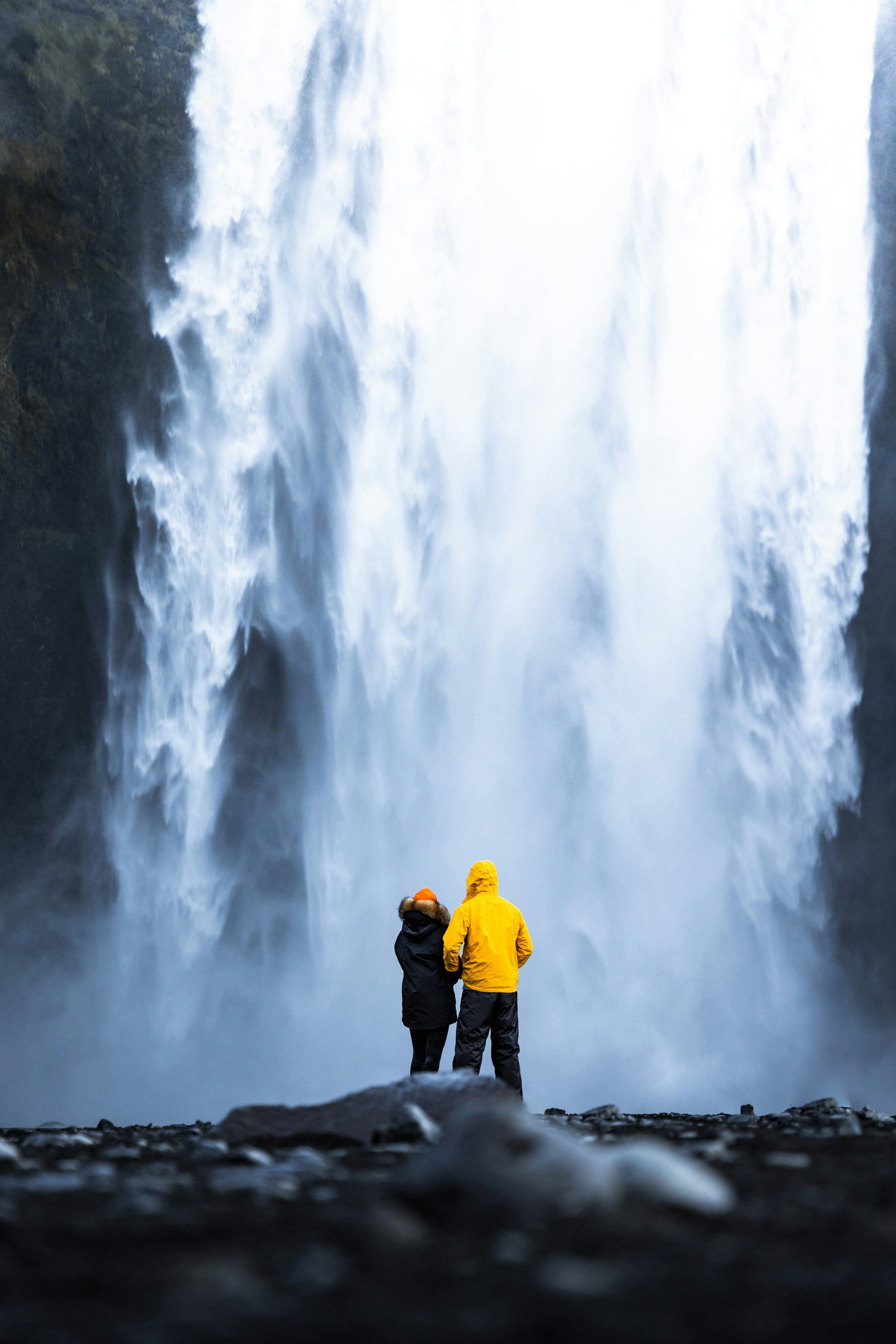 Storming Veil: Two Adventurers at the Base of a Wide Cascade