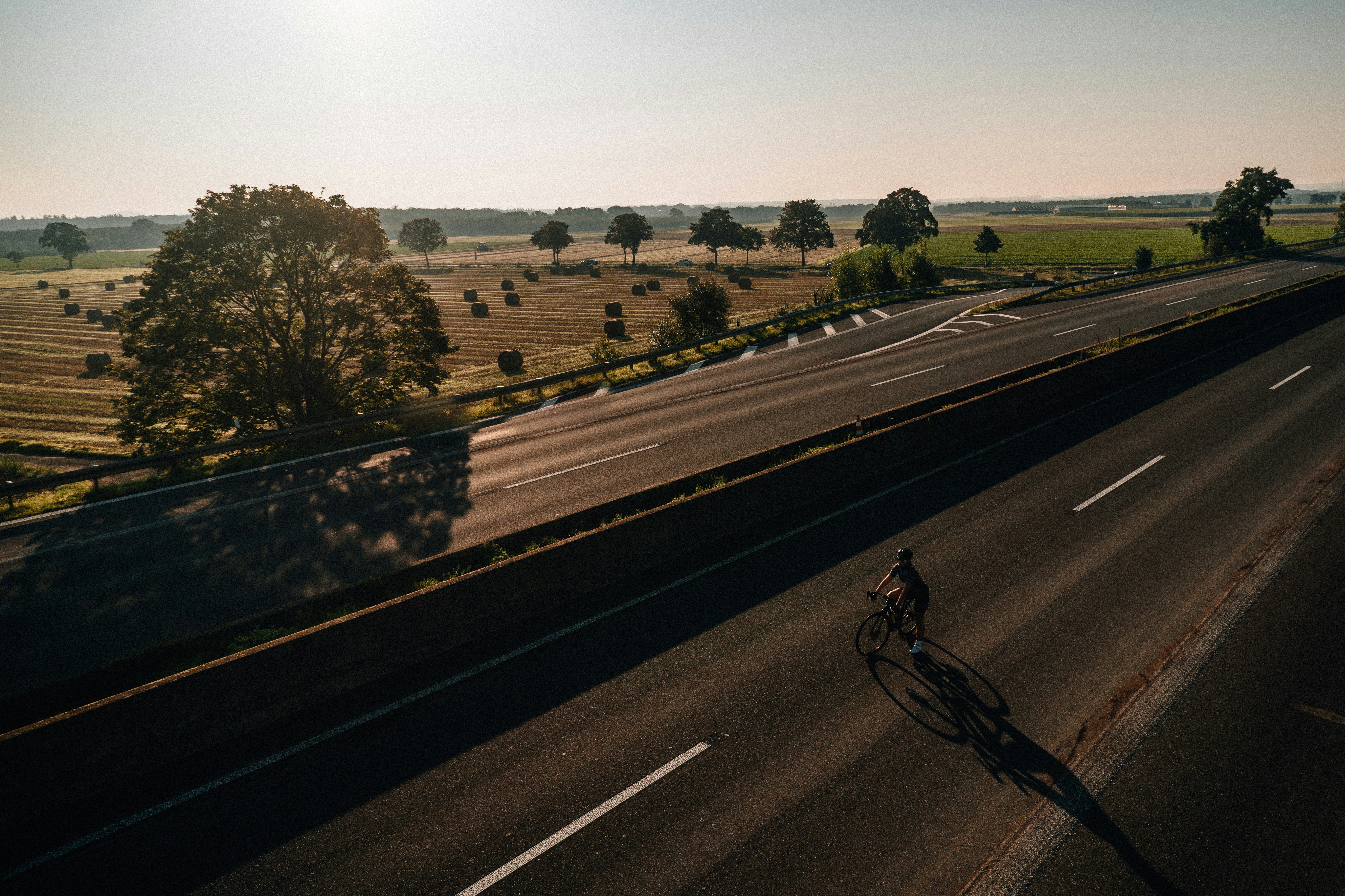 Golden Hour Ride: Cyclist Tracing Long Shadows on an Open Highway