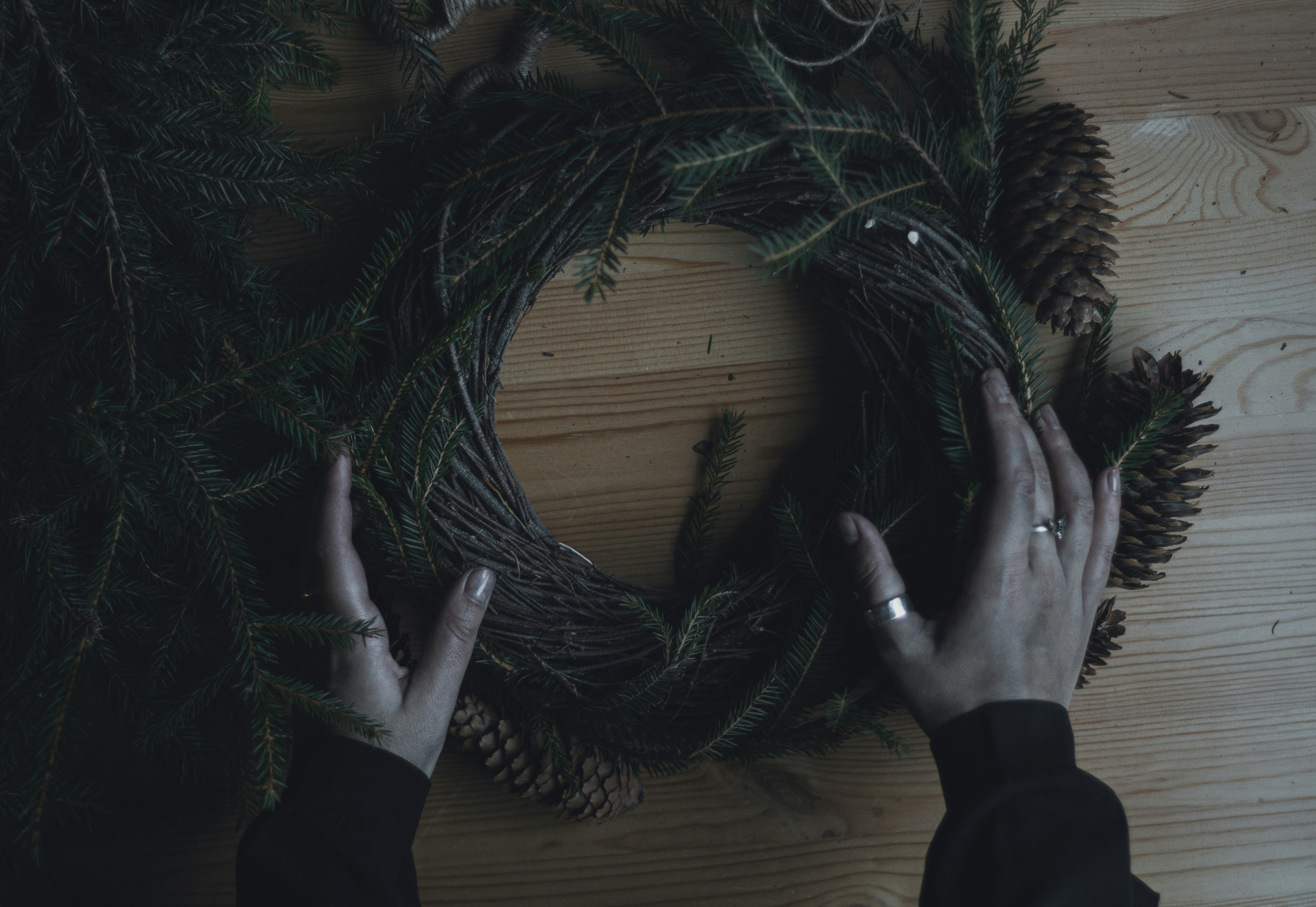 Framing Winter's Quiet: Hands Around a Pine Wreath on a Wooden Floor