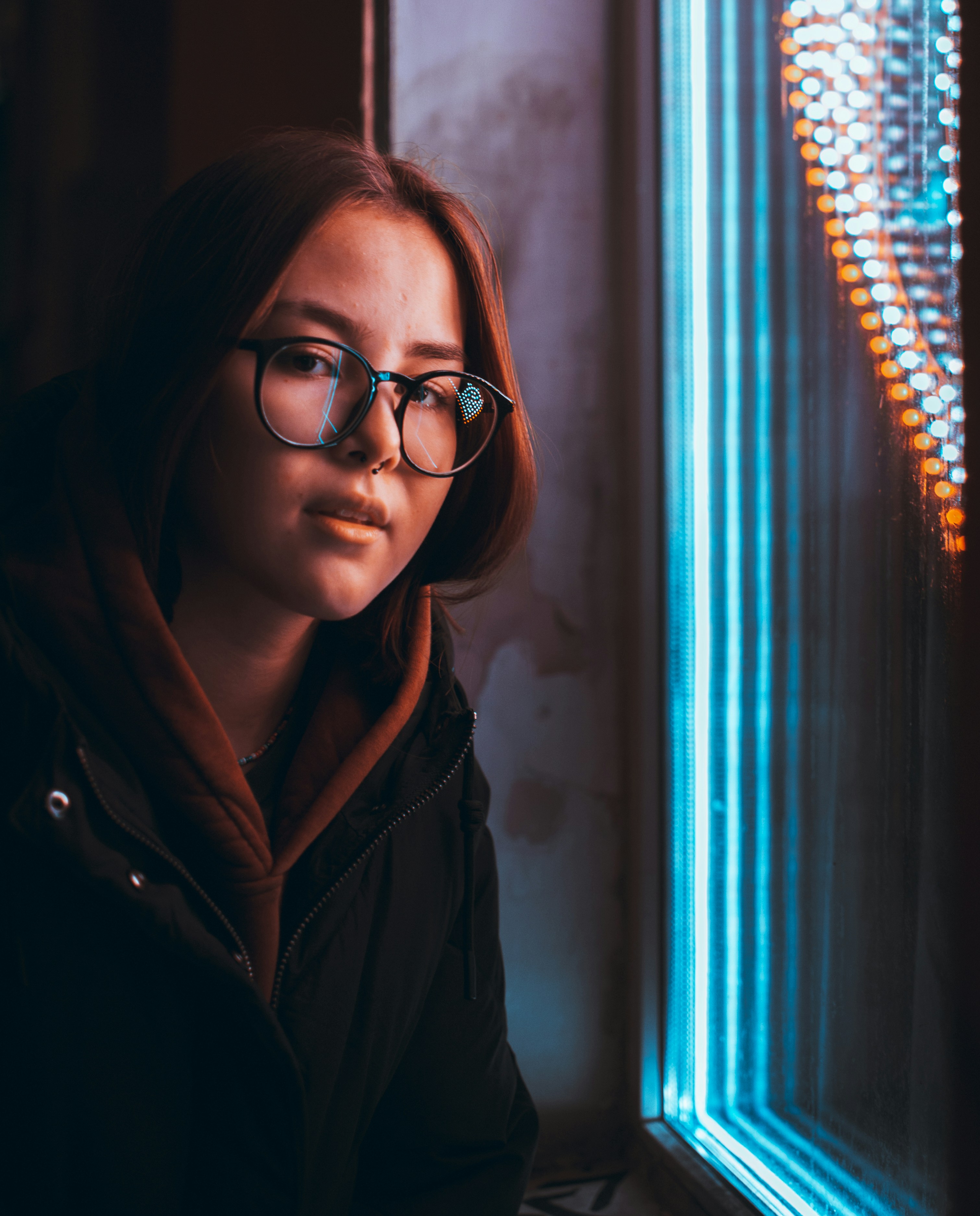 A woman wearing glasses looking out a window photo – Free Person Image ...