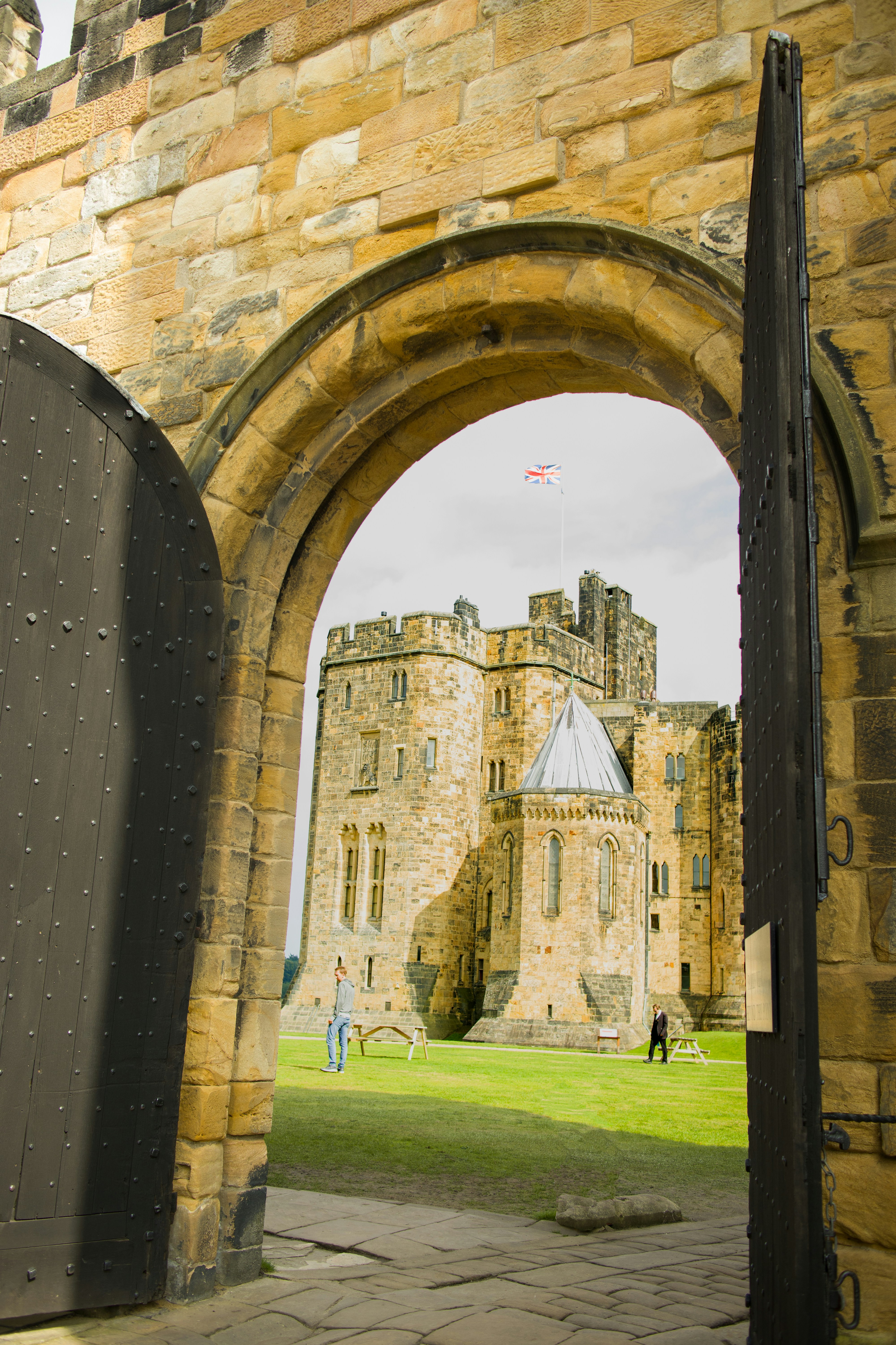 An archway leading to a castle with a kite flying in the sky photo ...