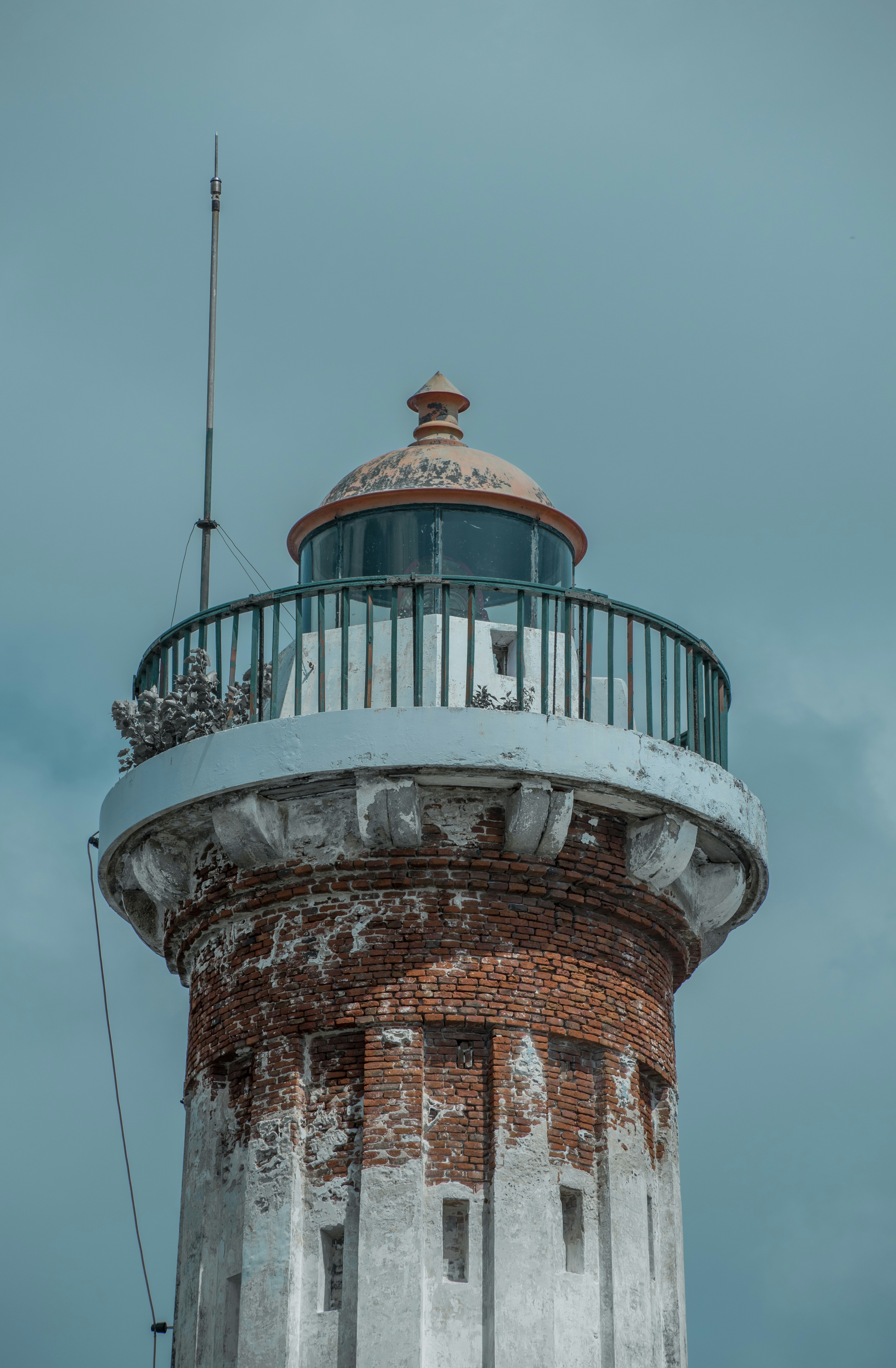 An old brick lighthouse with a weather vane on top photo – Free ...