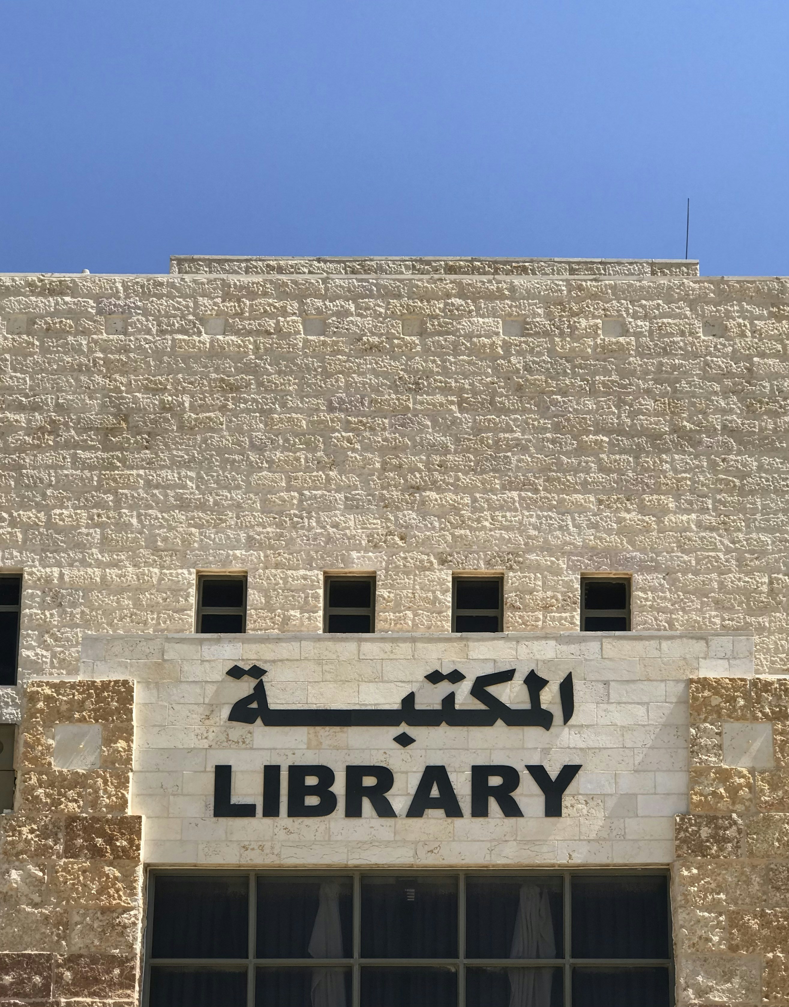 Facade of a library with bold signage under a clear blue sky.