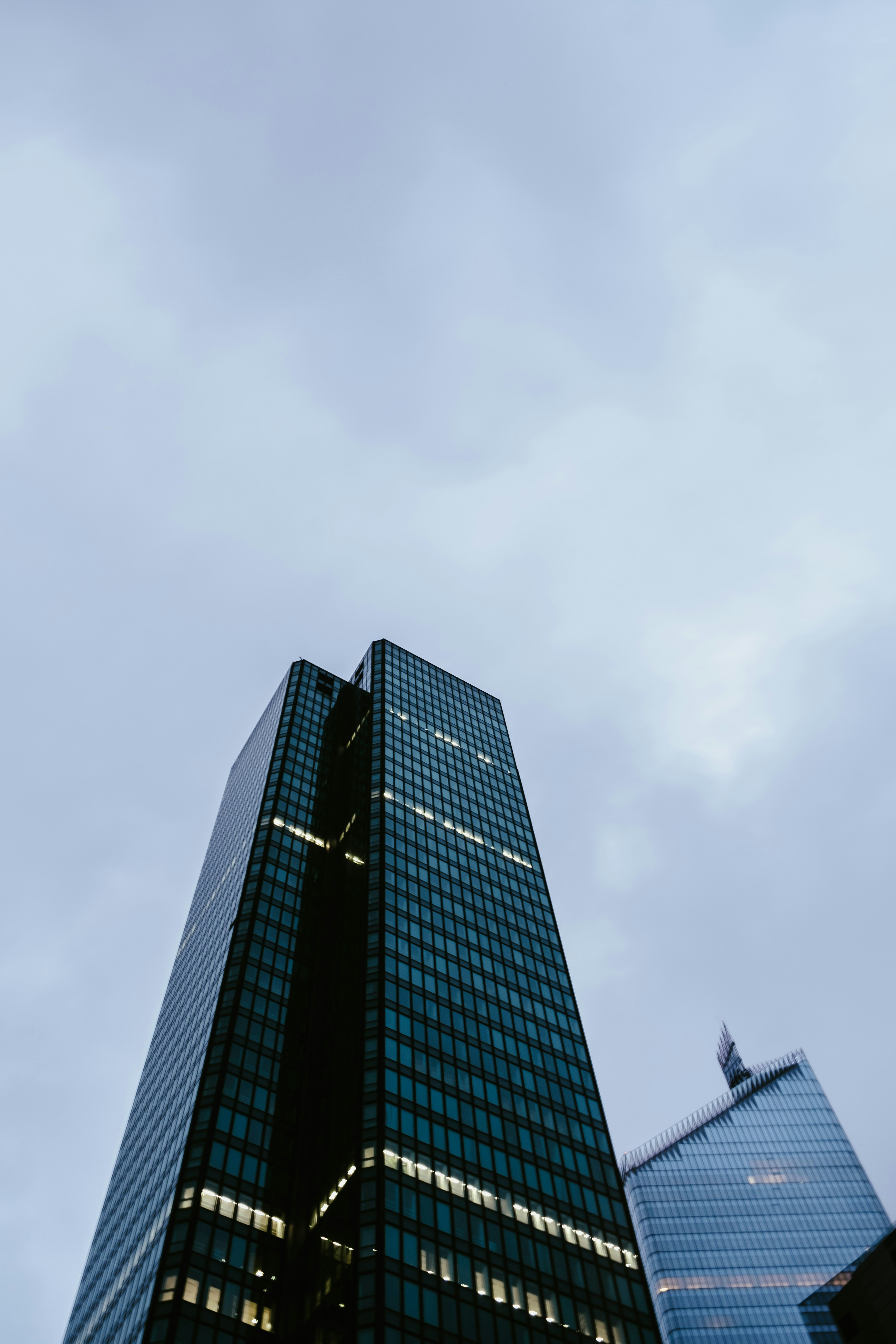 Skyscrapers reaching towards the cloudy sky, showcasing modern architectural design and reflective glass surfaces.
