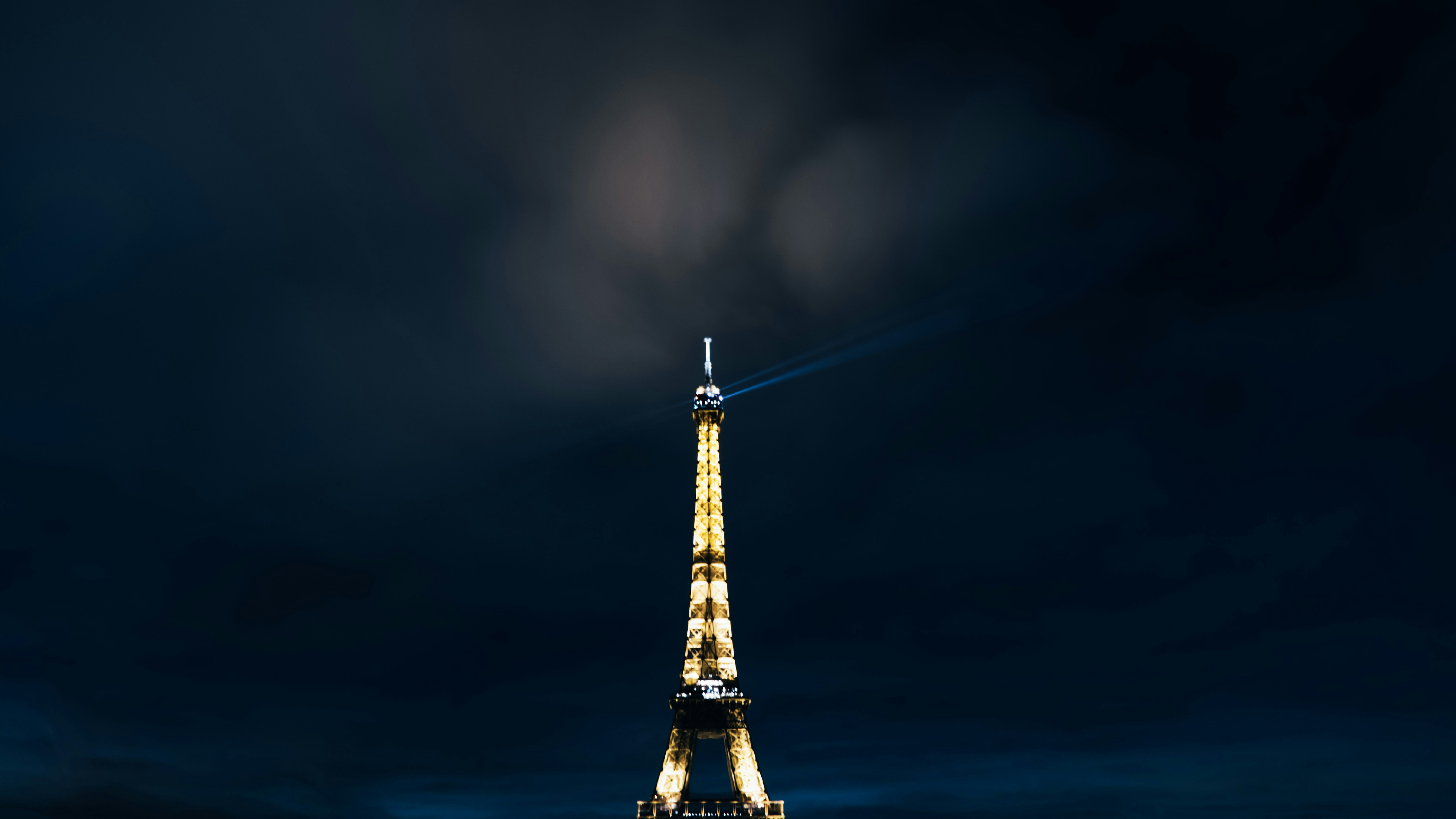 Eiffel Tower illuminated against a dark Paris night sky, captured from a central viewpoint.