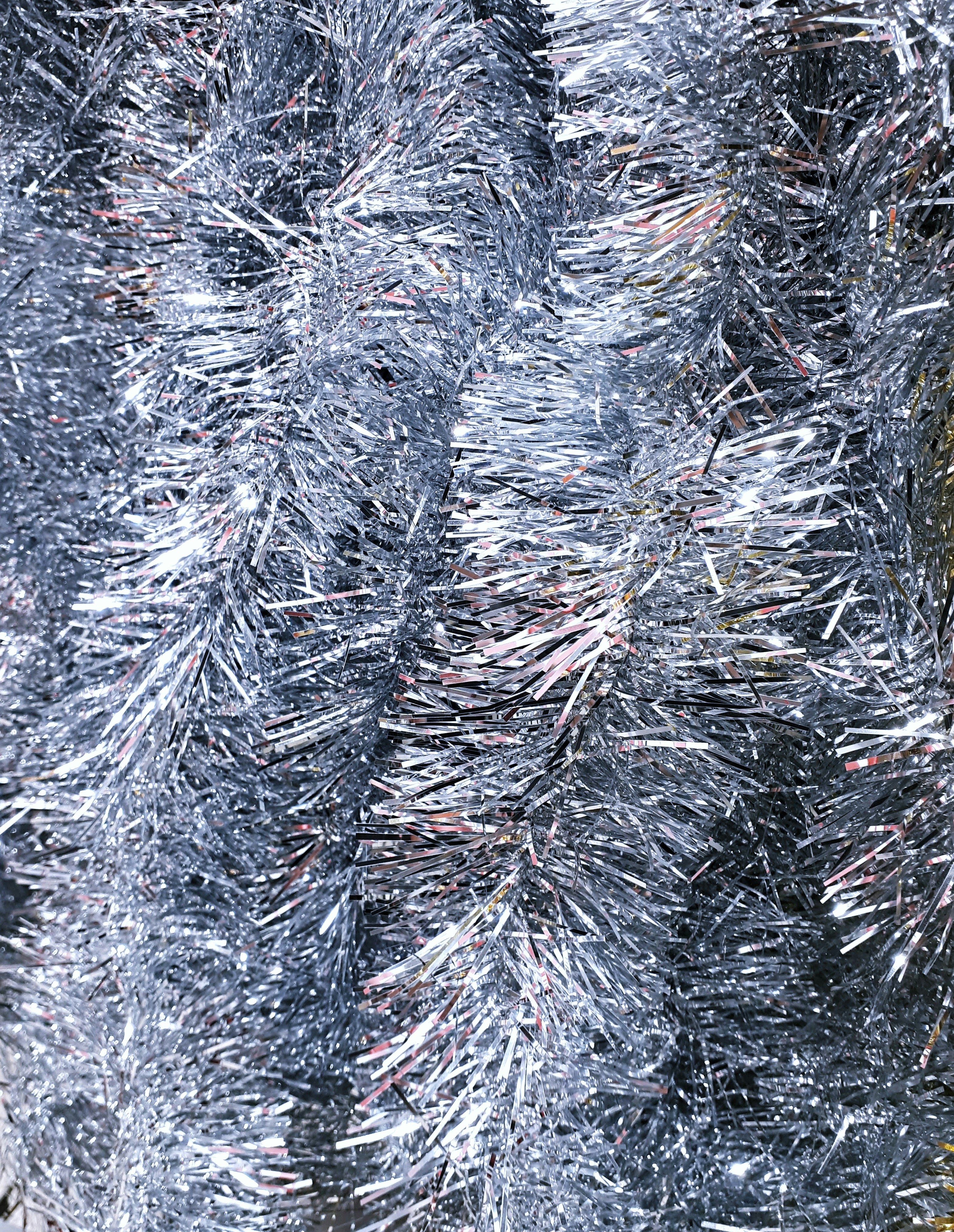 Close-up of shimmering silver tinsel, reflecting light and creating a festive atmosphere.