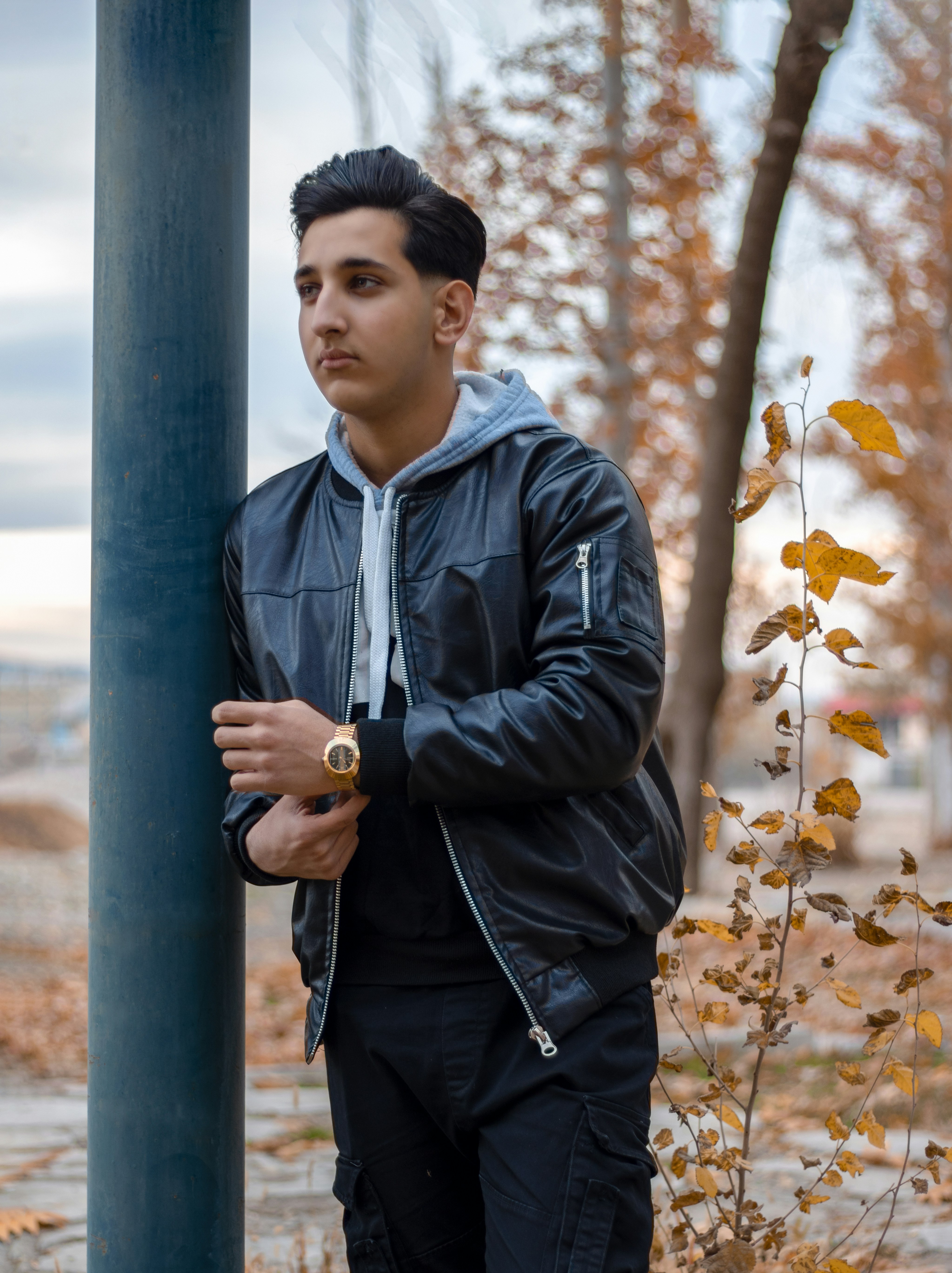 A man leaning against a pole in a park photo – Free Man Image on Unsplash