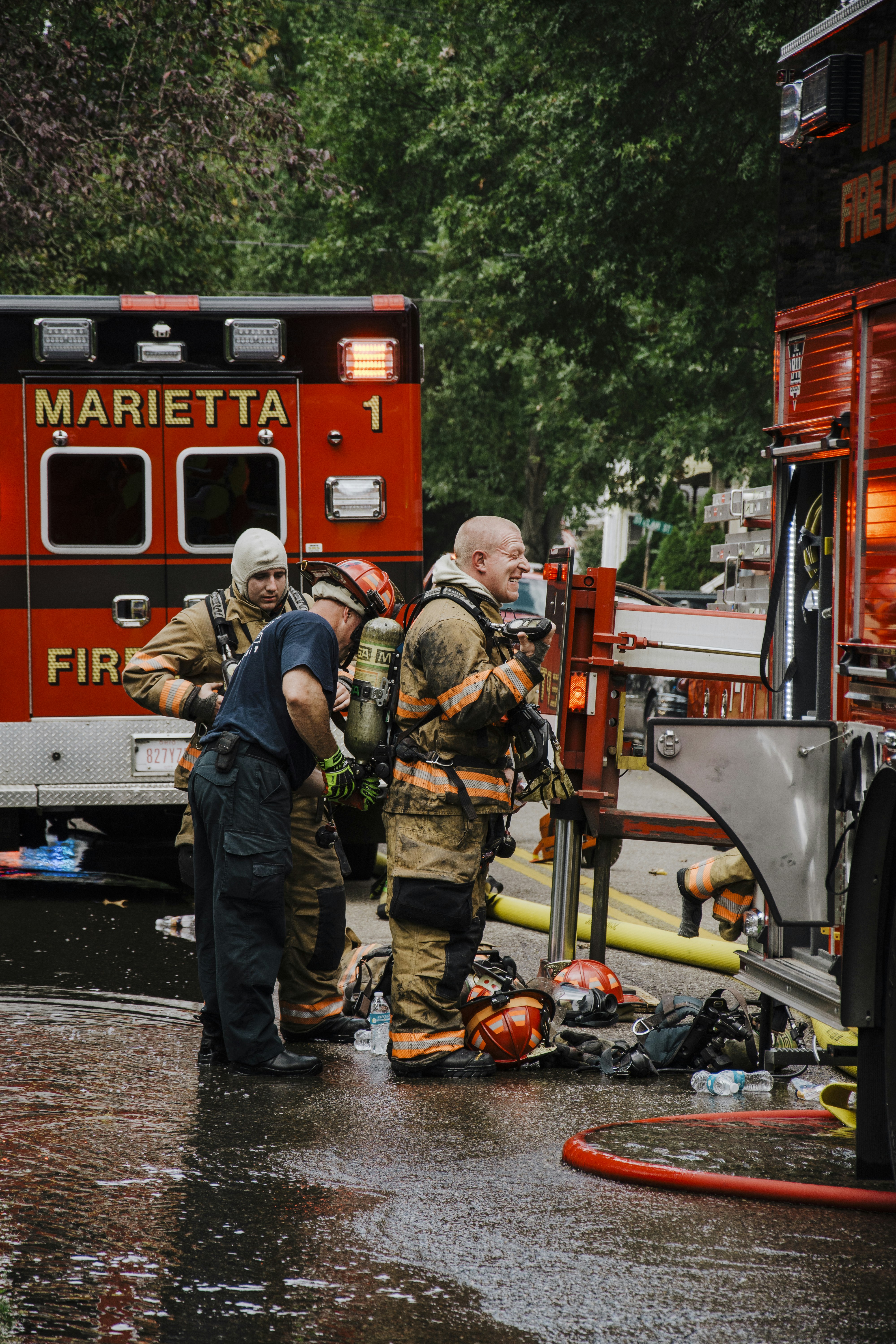 A group of firefighters standing around a fire truck photo – Free ...