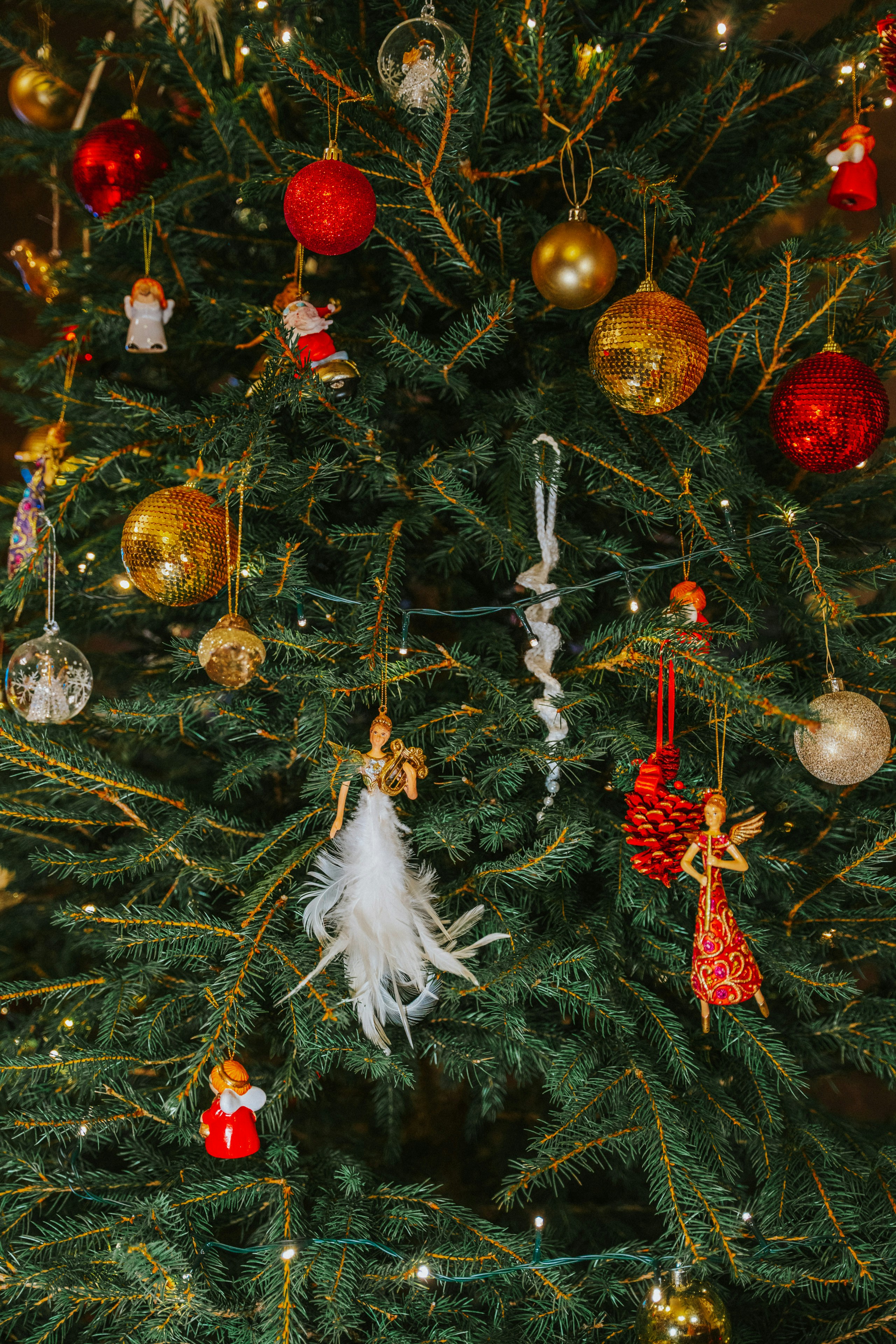 A richly adorned Christmas tree featuring a variety of colorful ornaments and charming decorations, creating a festive atmosphere.