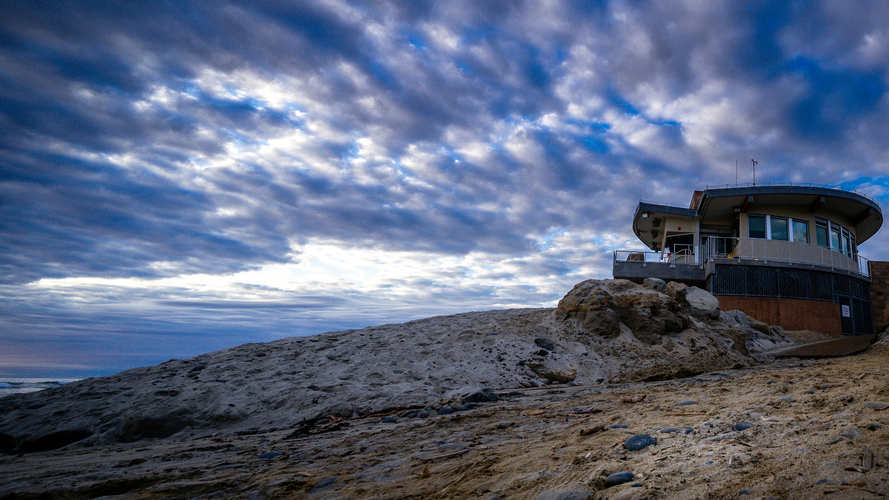 a house sitting on top of a sandy hill