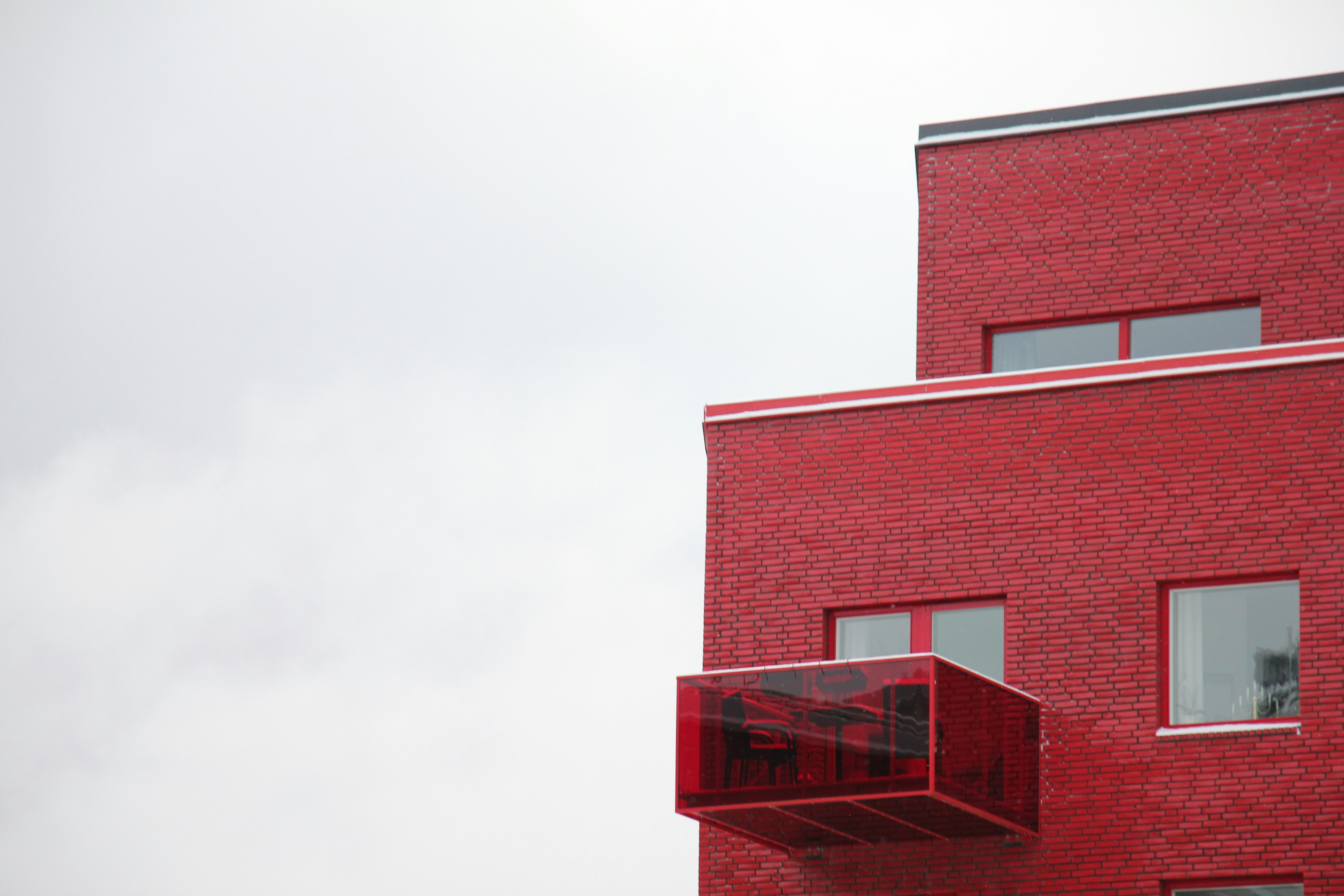 Crimson Balcony Protrudes from a Red Brick Facade