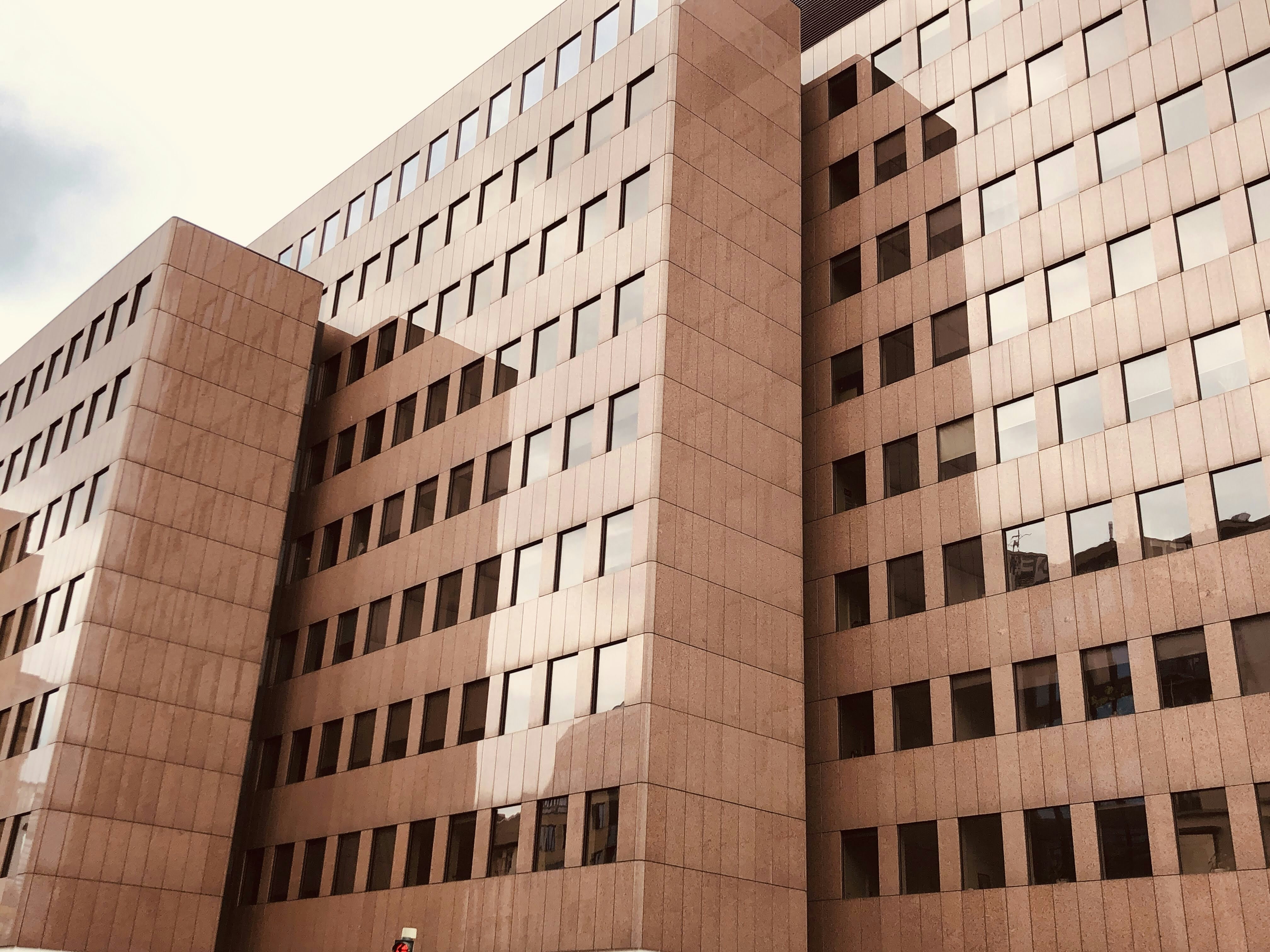 A tall brown building with lots of windows photo – Free Office building ...
