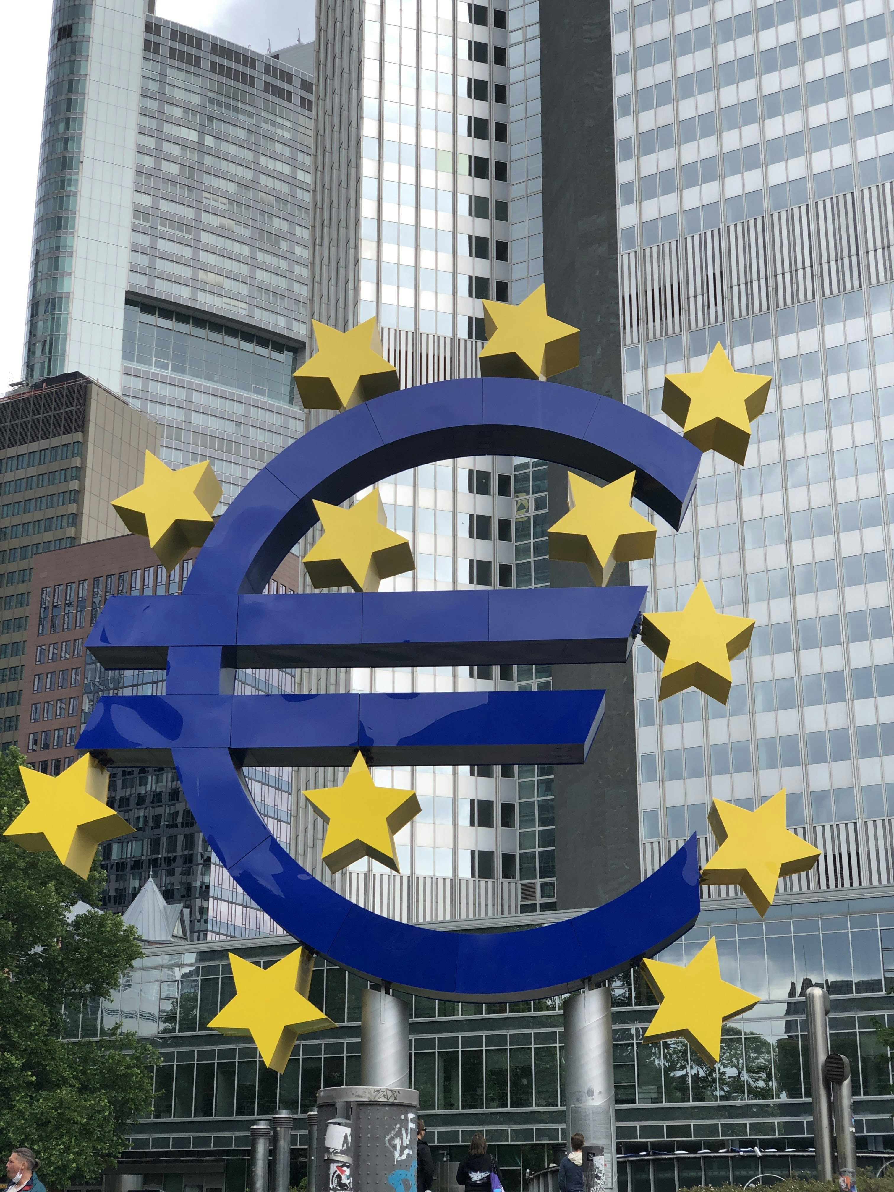 Euro Sign in the City: Blue Circle with Yellow Stars Above Glass Skyscrapers