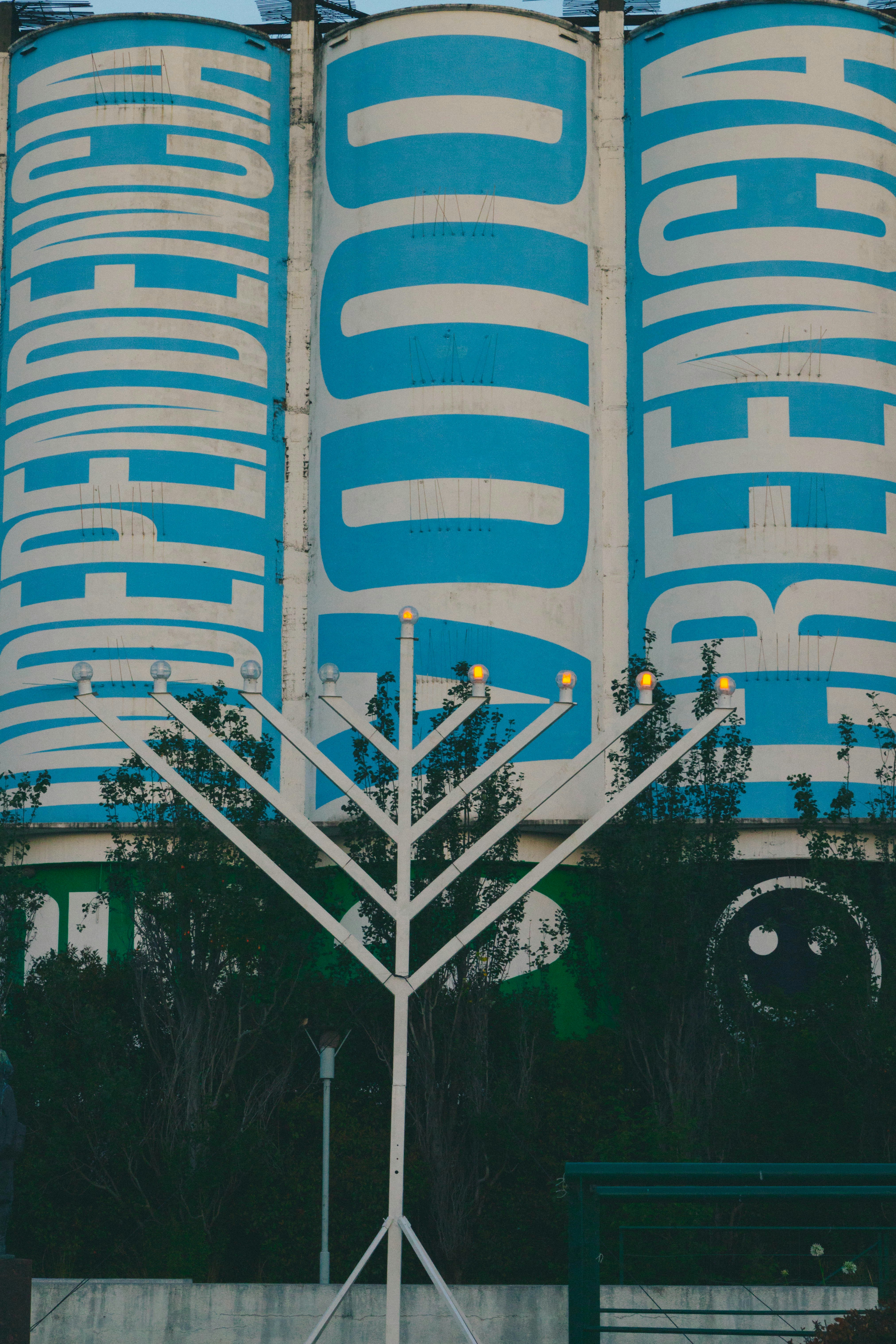 A tall blue building with a tall metal menorah in front of it photo ...