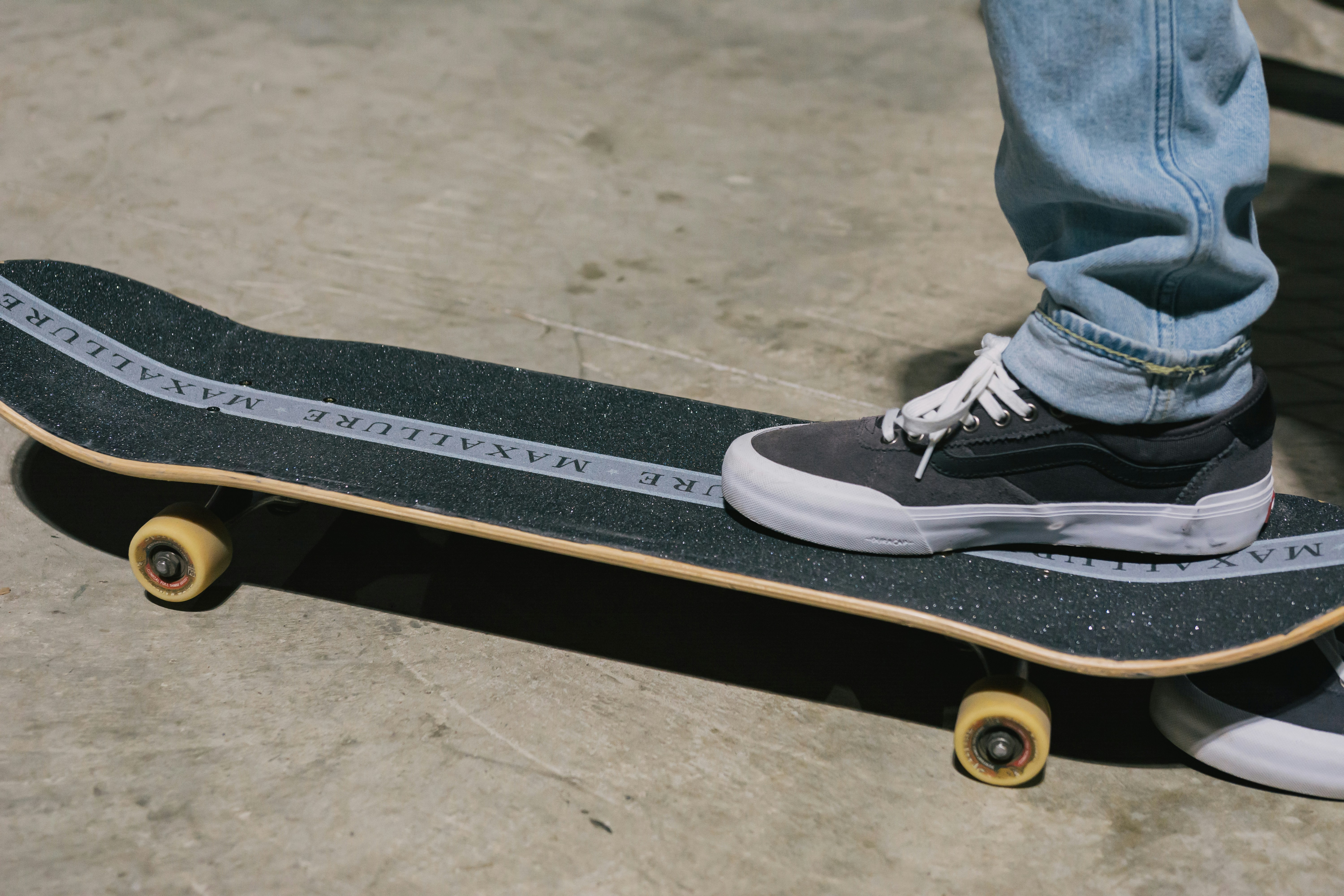 Foot poised on a skateboard, ready for action on a concrete surface.