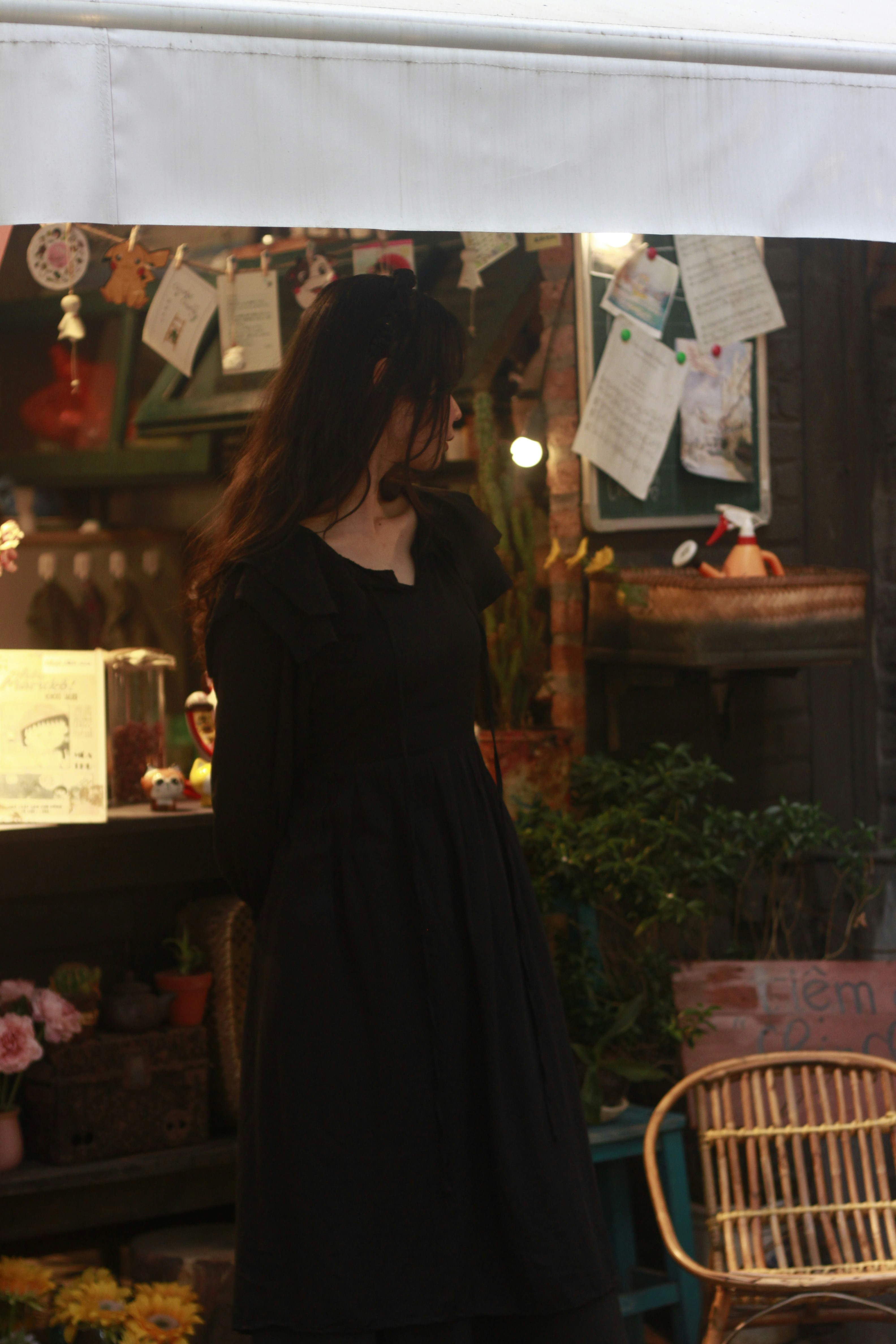Midnight Dress, Market Lights: a Quiet Portrait Among Cards and Plants