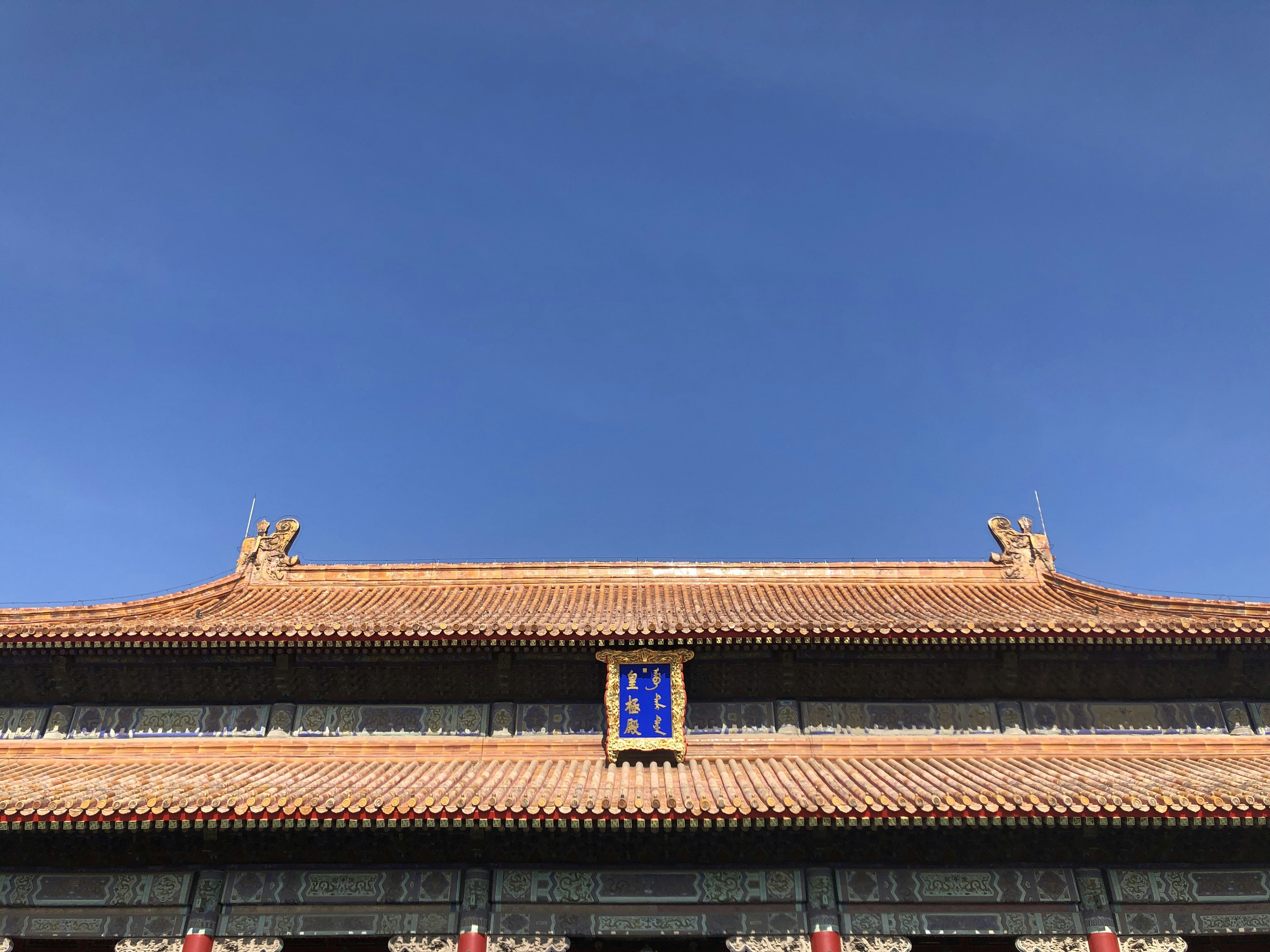 Ornate rooftop of a historic building under a clear blue sky, showcasing intricate design and vibrant colors.