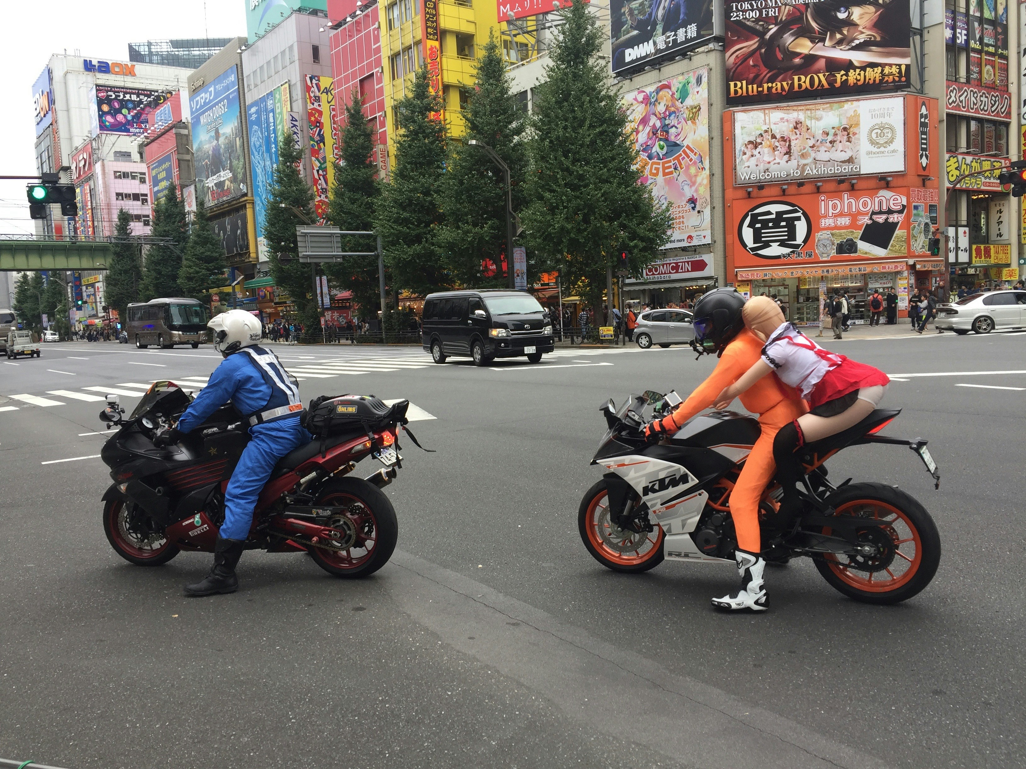A couple of people riding motorcycles down a street photo – Free Car ...