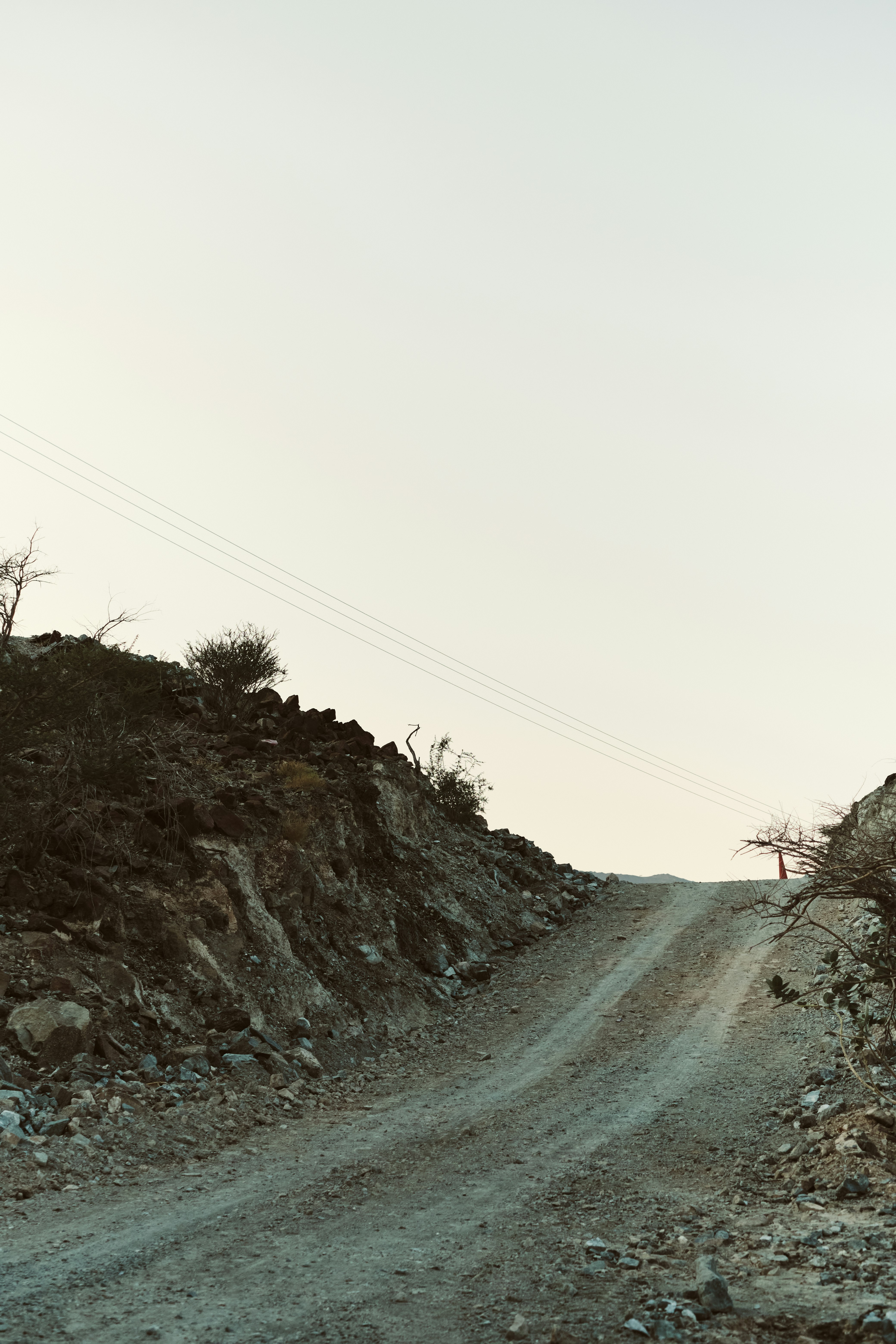 a dirt road with a hill in the background