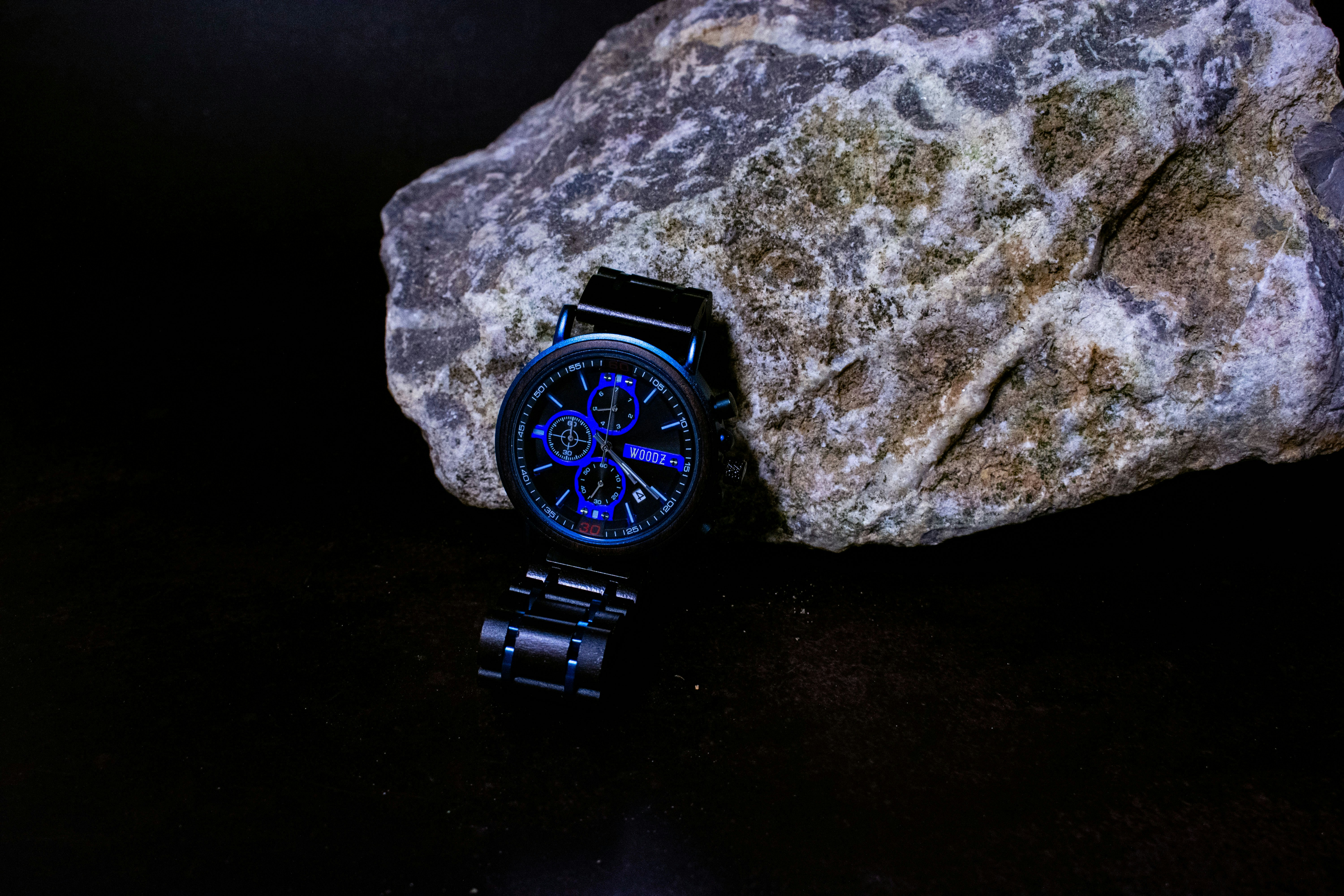 Blue-Dial Chronograph Resting Against a Rugged Rock in Low Light
