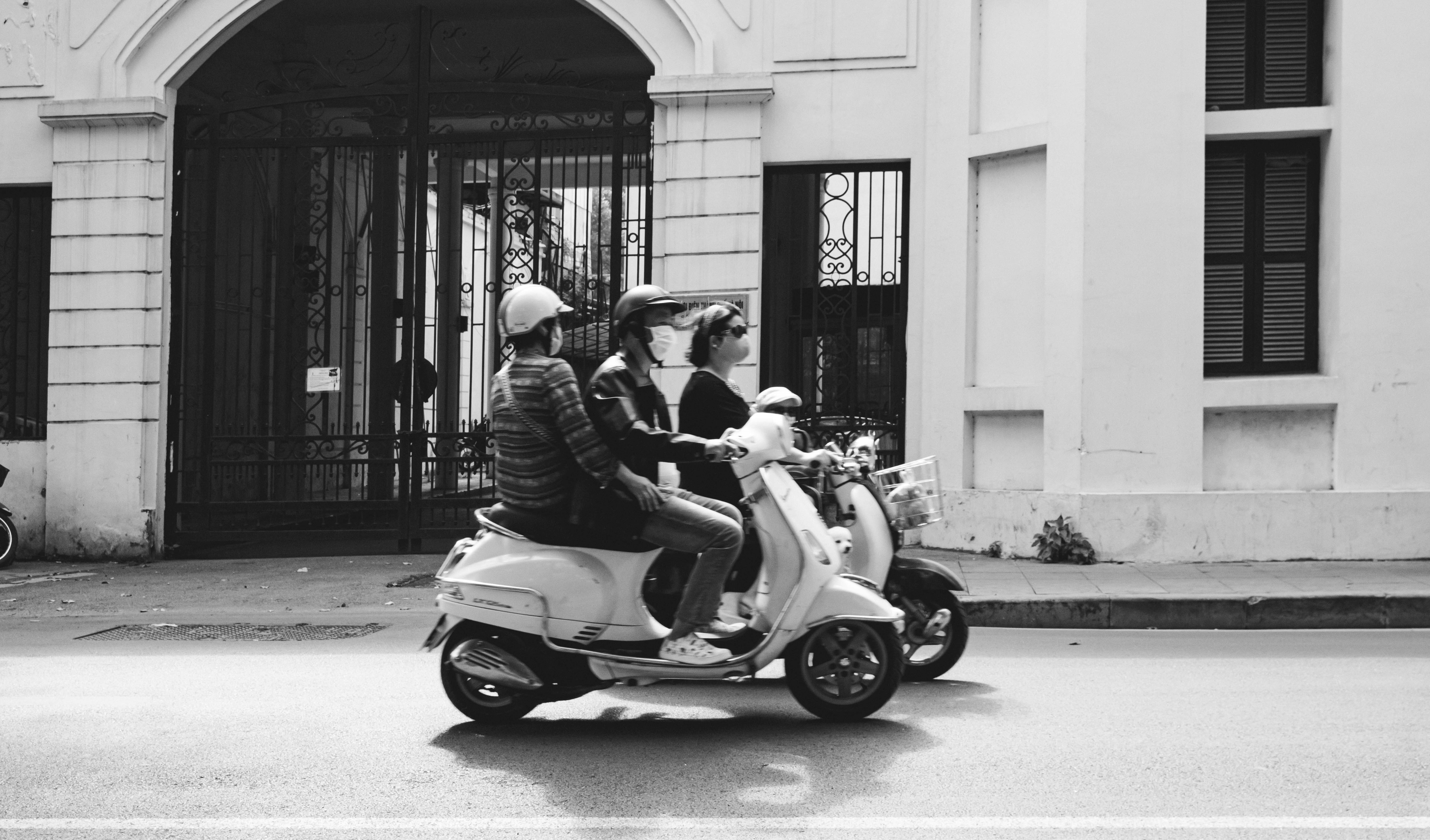 Grayscale Glide: A Family on a Vespa Before the Arched Gate