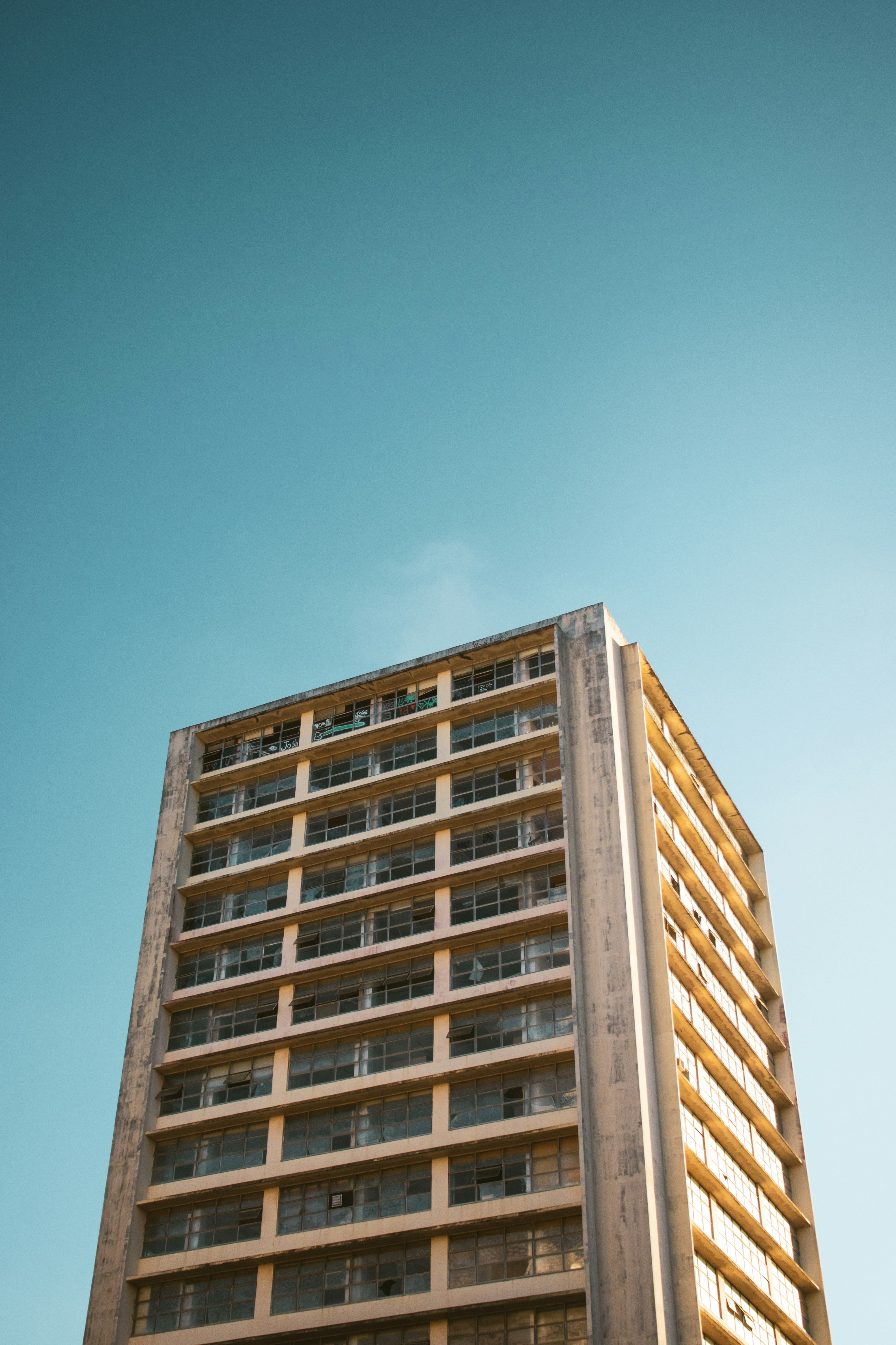 Modernist building reaching towards the sky, showcasing a blend of concrete and glass against a clear blue backdrop.