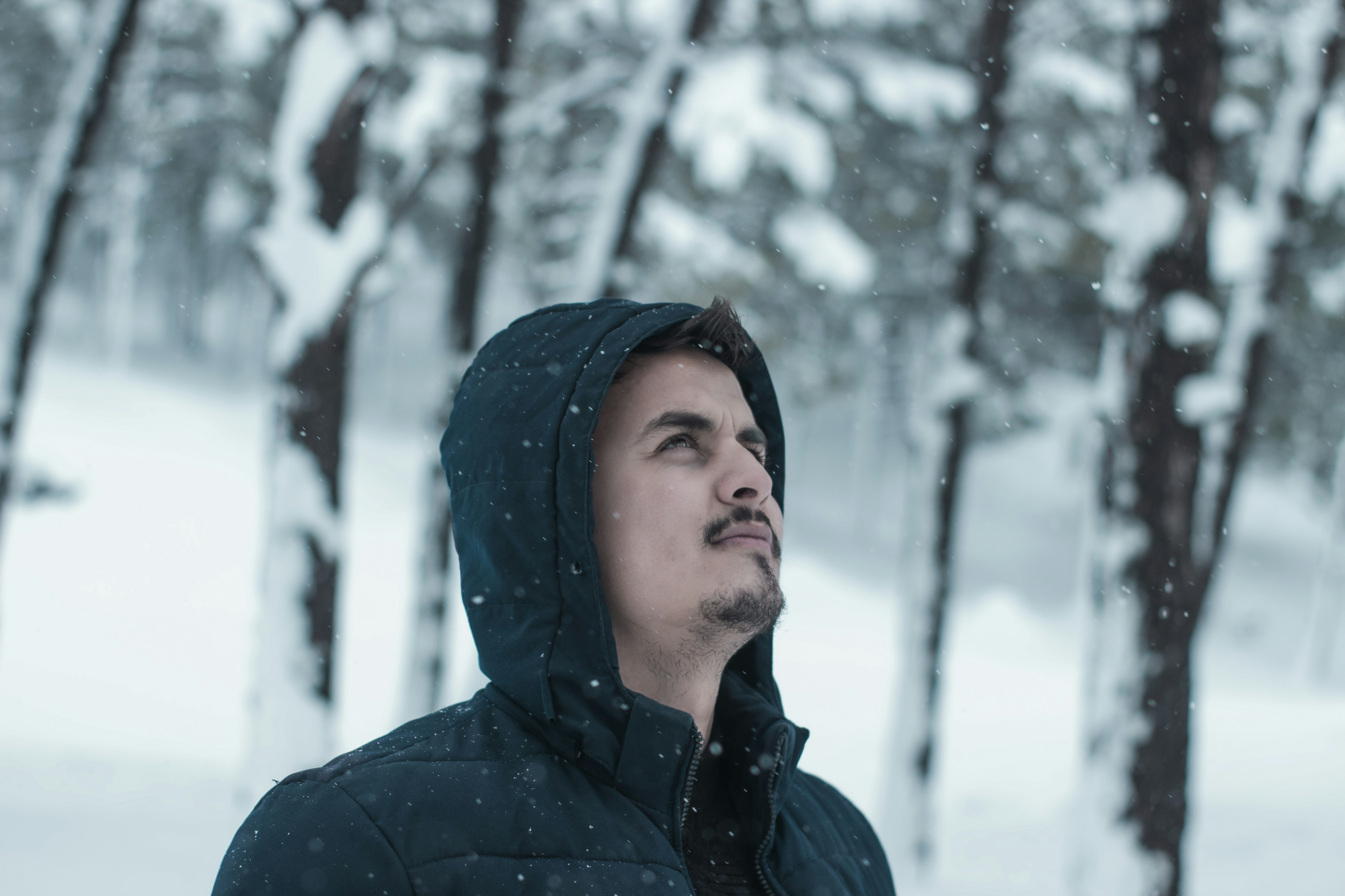 Winter Gaze: Hooded Portrait Beneath Falling Snow
