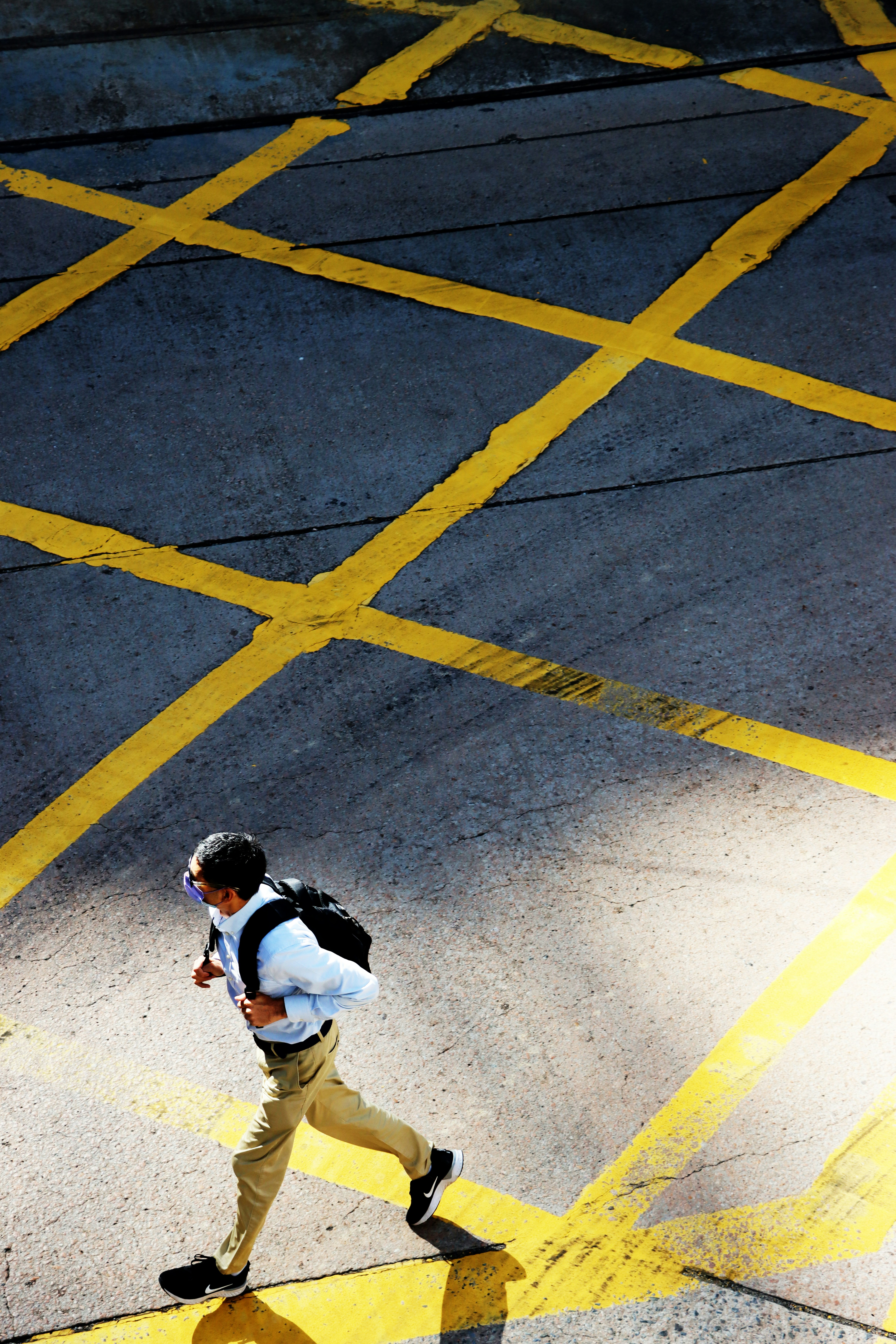 A man walking across a street with a backpack photo – Free Central ...